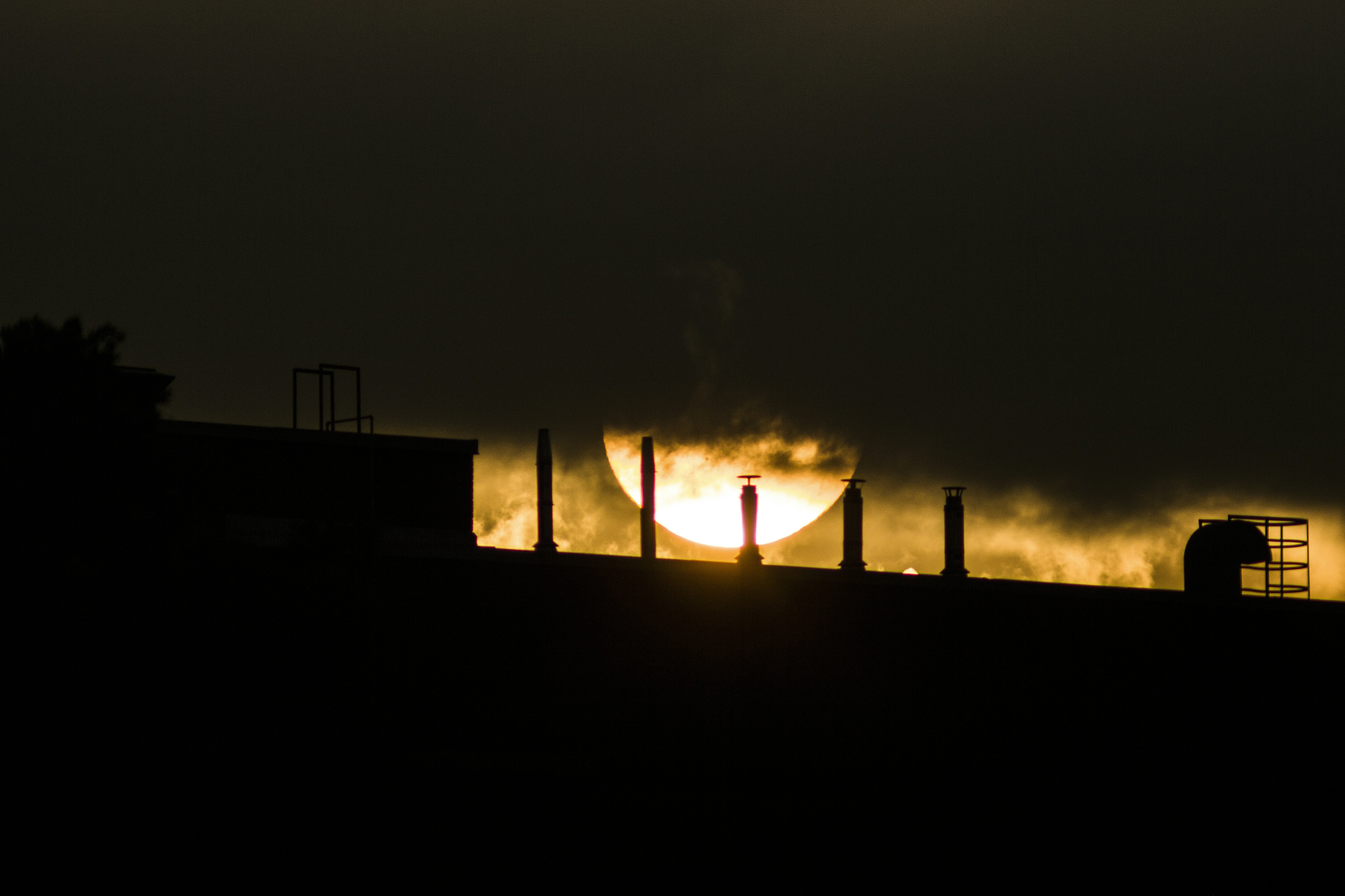 Sunset silhouette: a lone figure against a smokey skyline on the rooftop