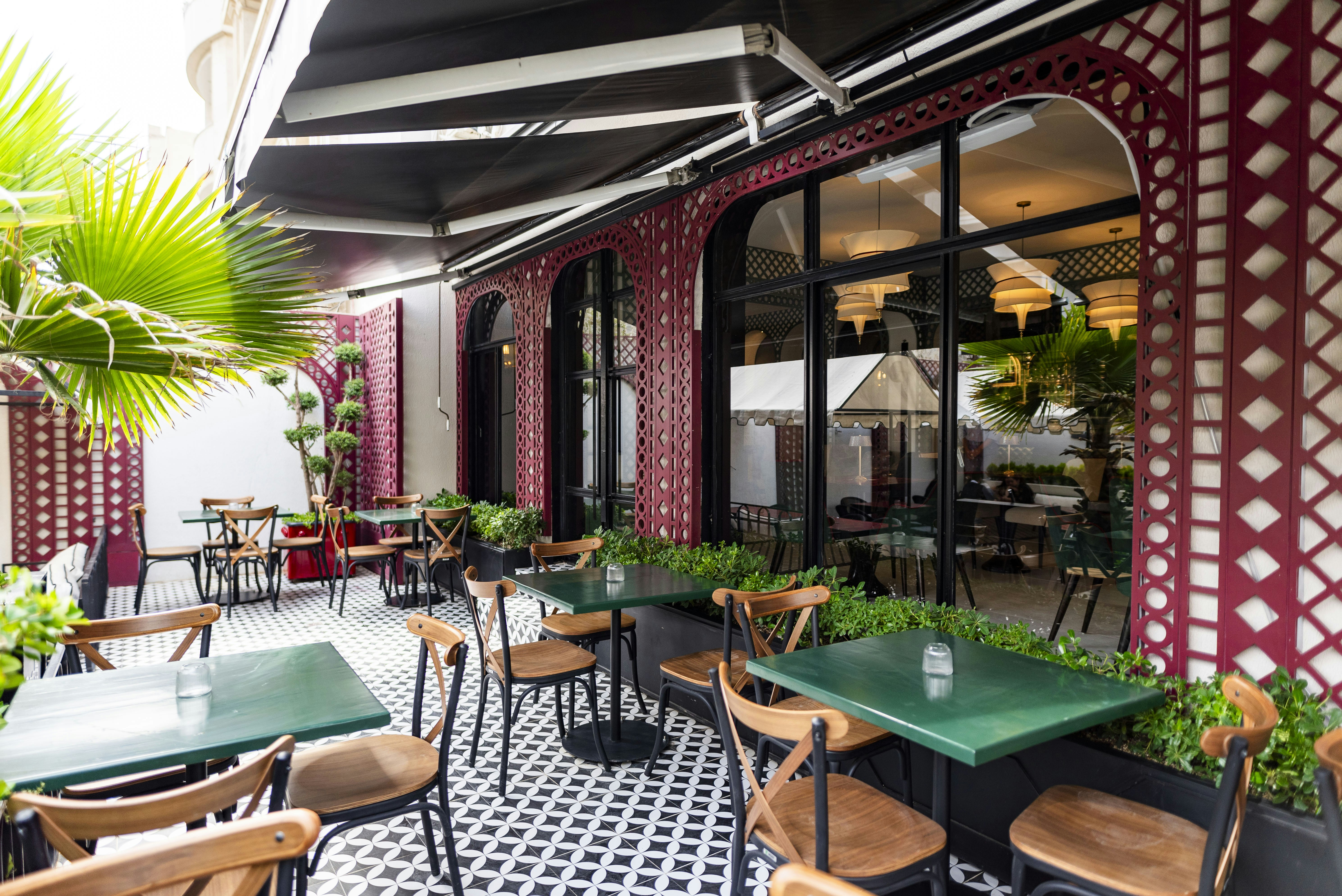 Sunlit Terrace of Geometric Ironwork and Green Tables
