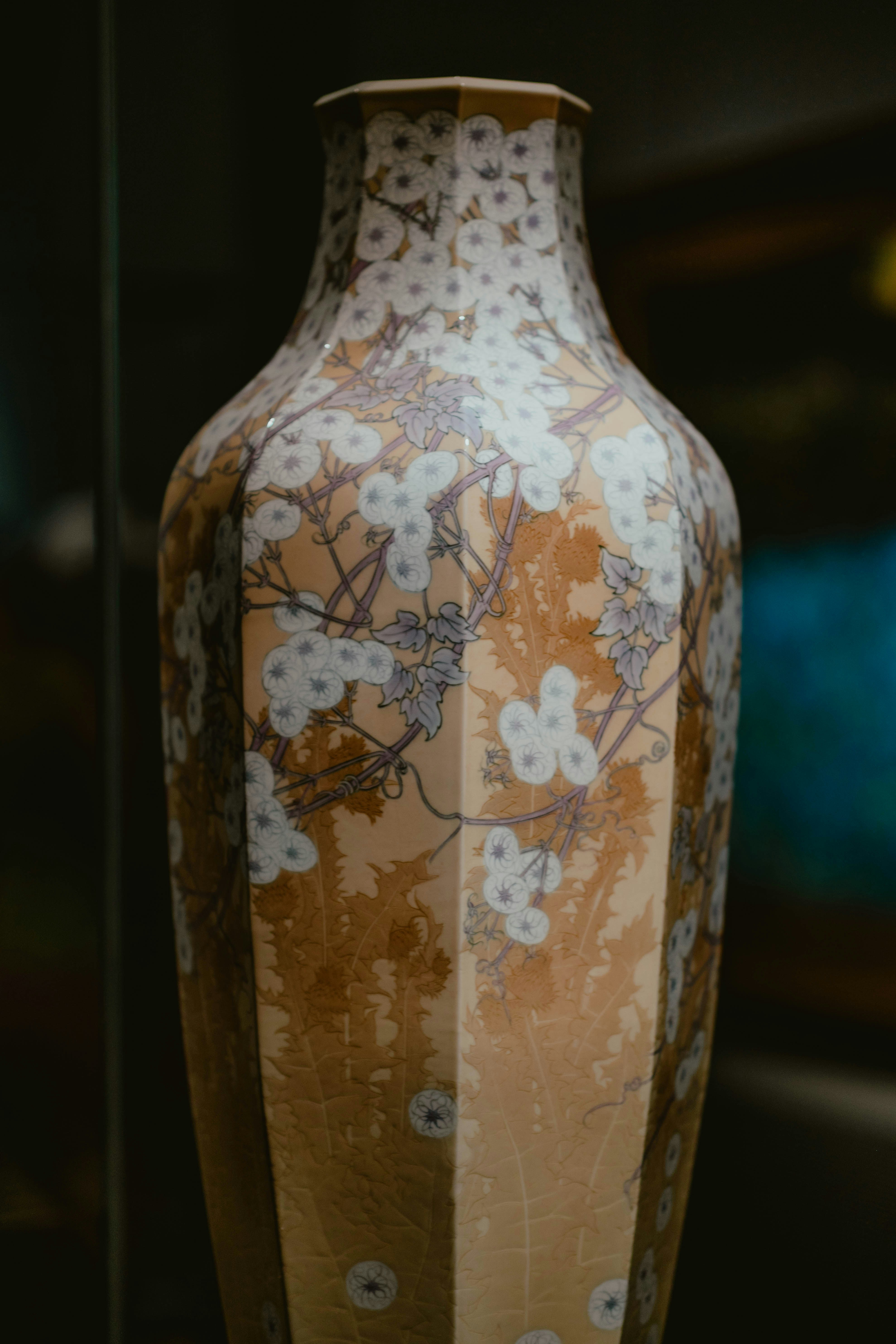 A tall ceramic vase decorated with white flowers and brown foliage patterns