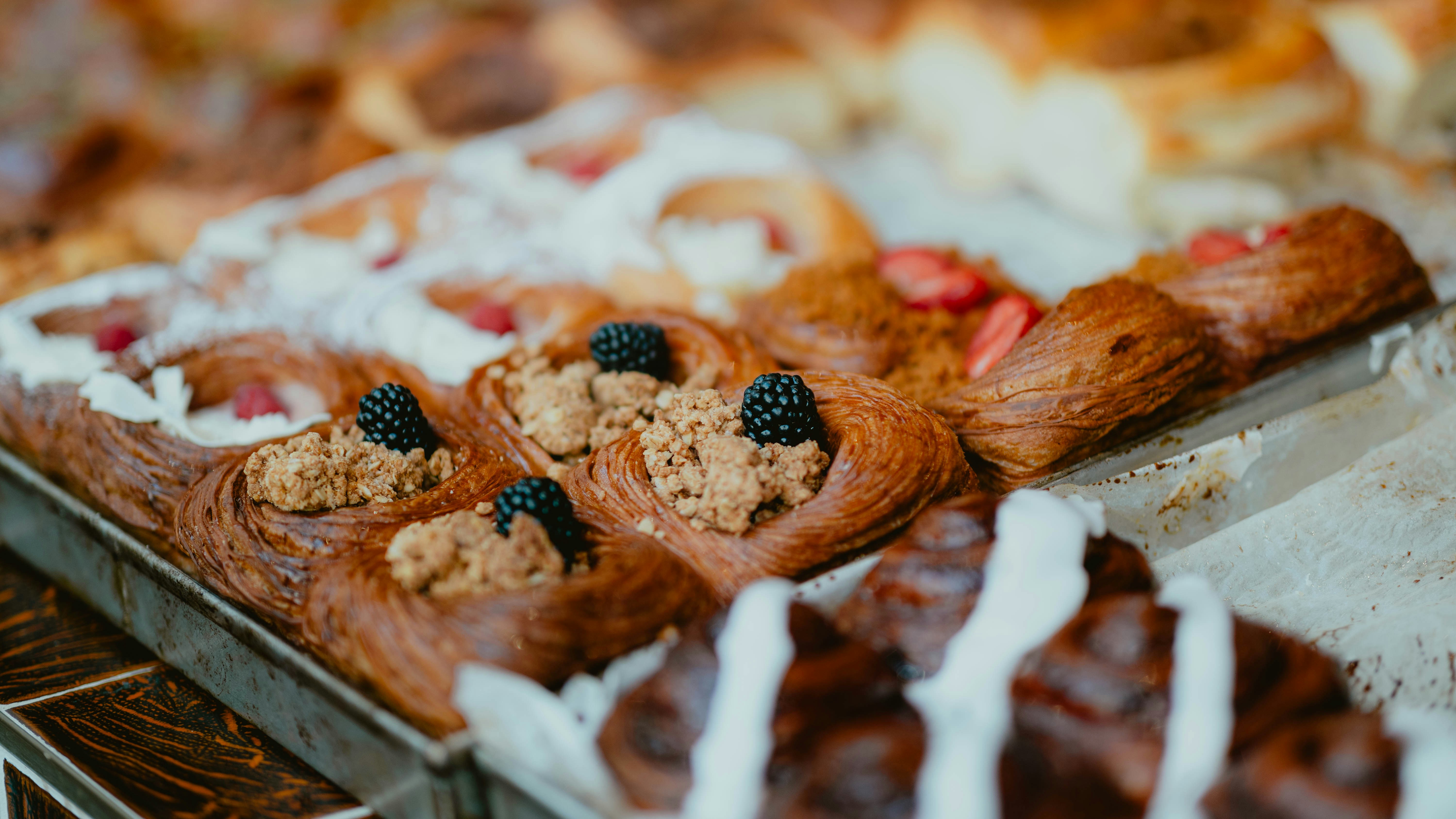 Chocolate-brown pastries with blackberry accents on a pastry tray