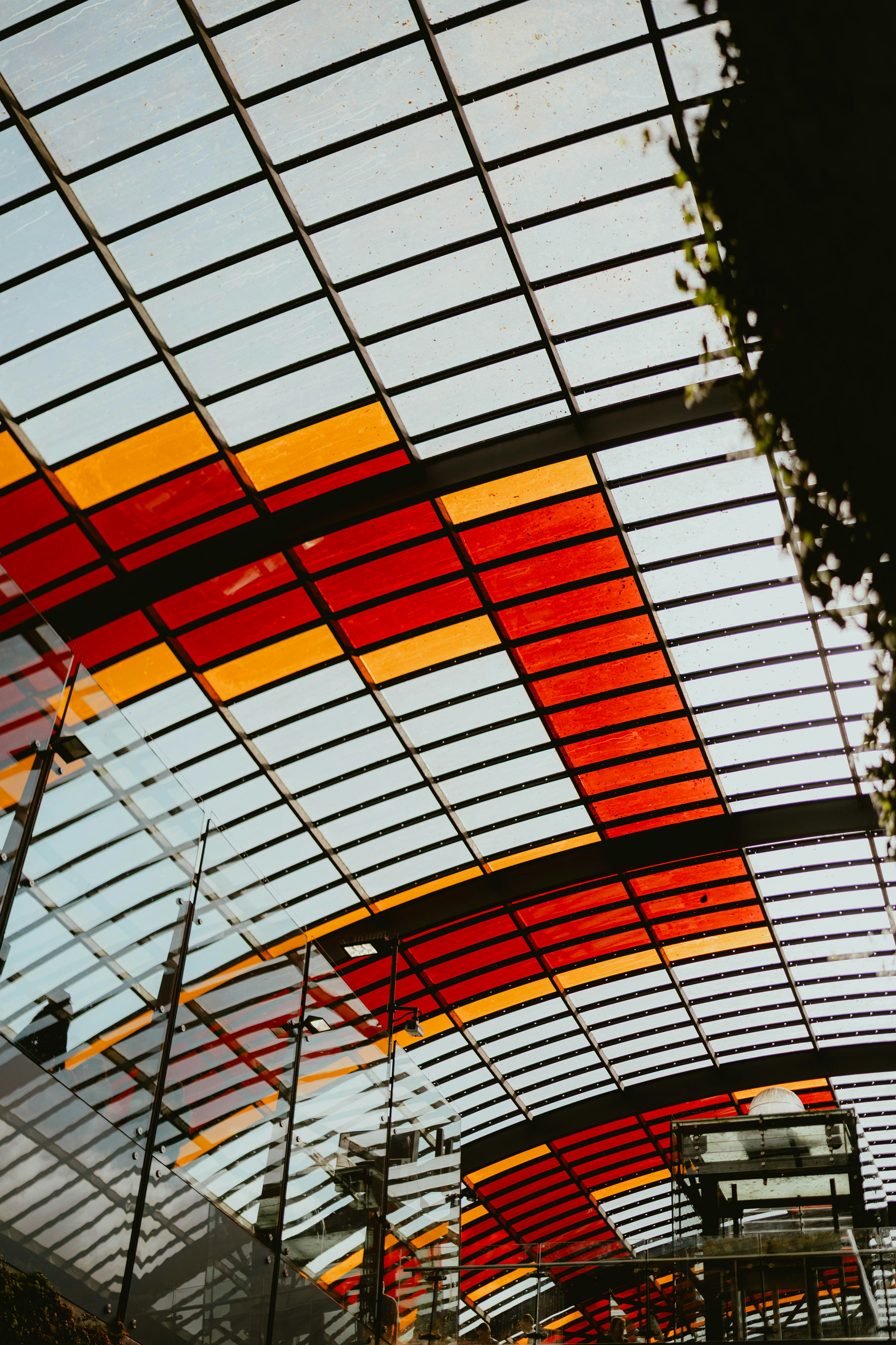 Colored Glass Canopy Overhead: A Rhythm of Red, Orange, and Sunlight