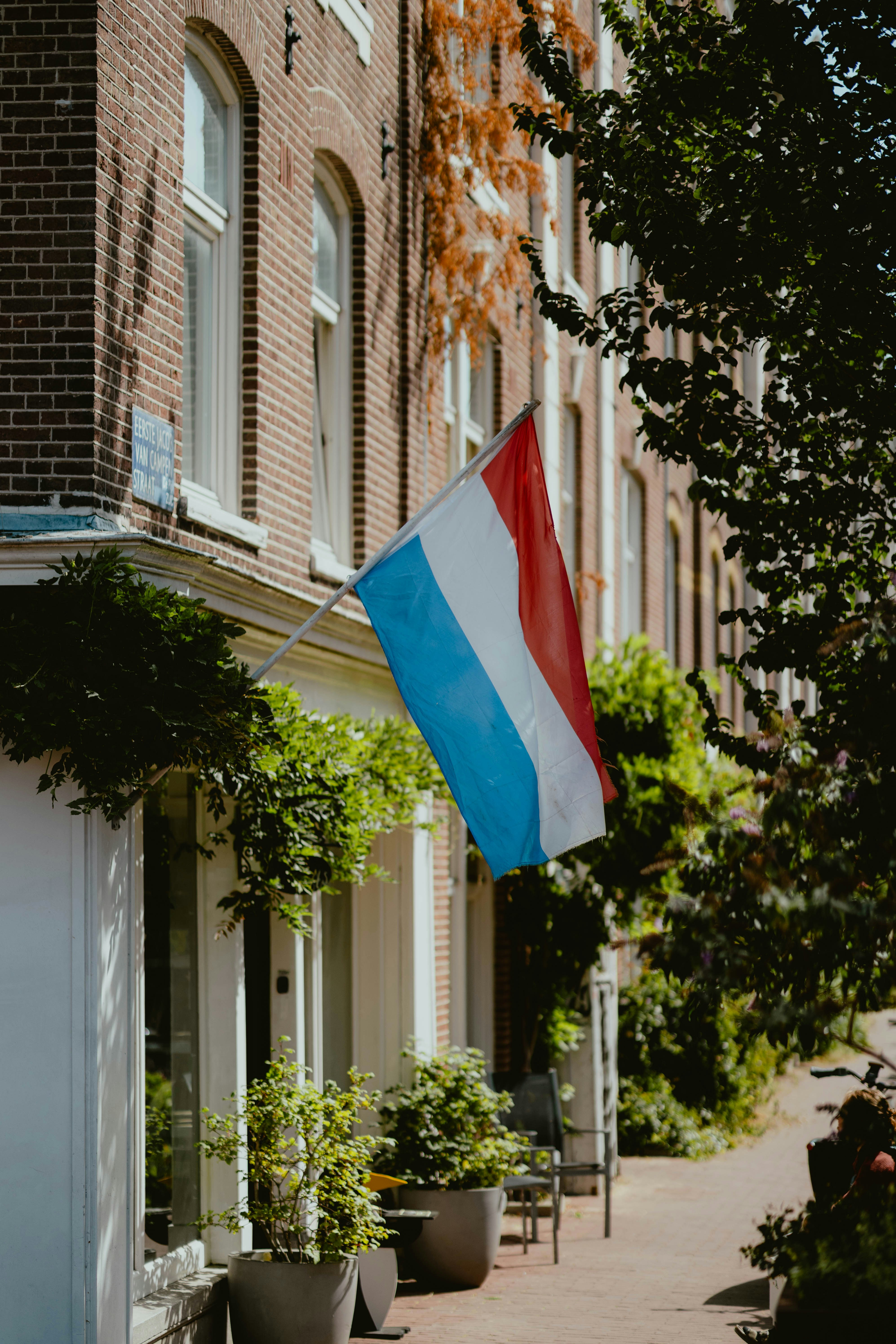 Flag on a Sunlit Brick Street Swaying Along a Quiet Corridor