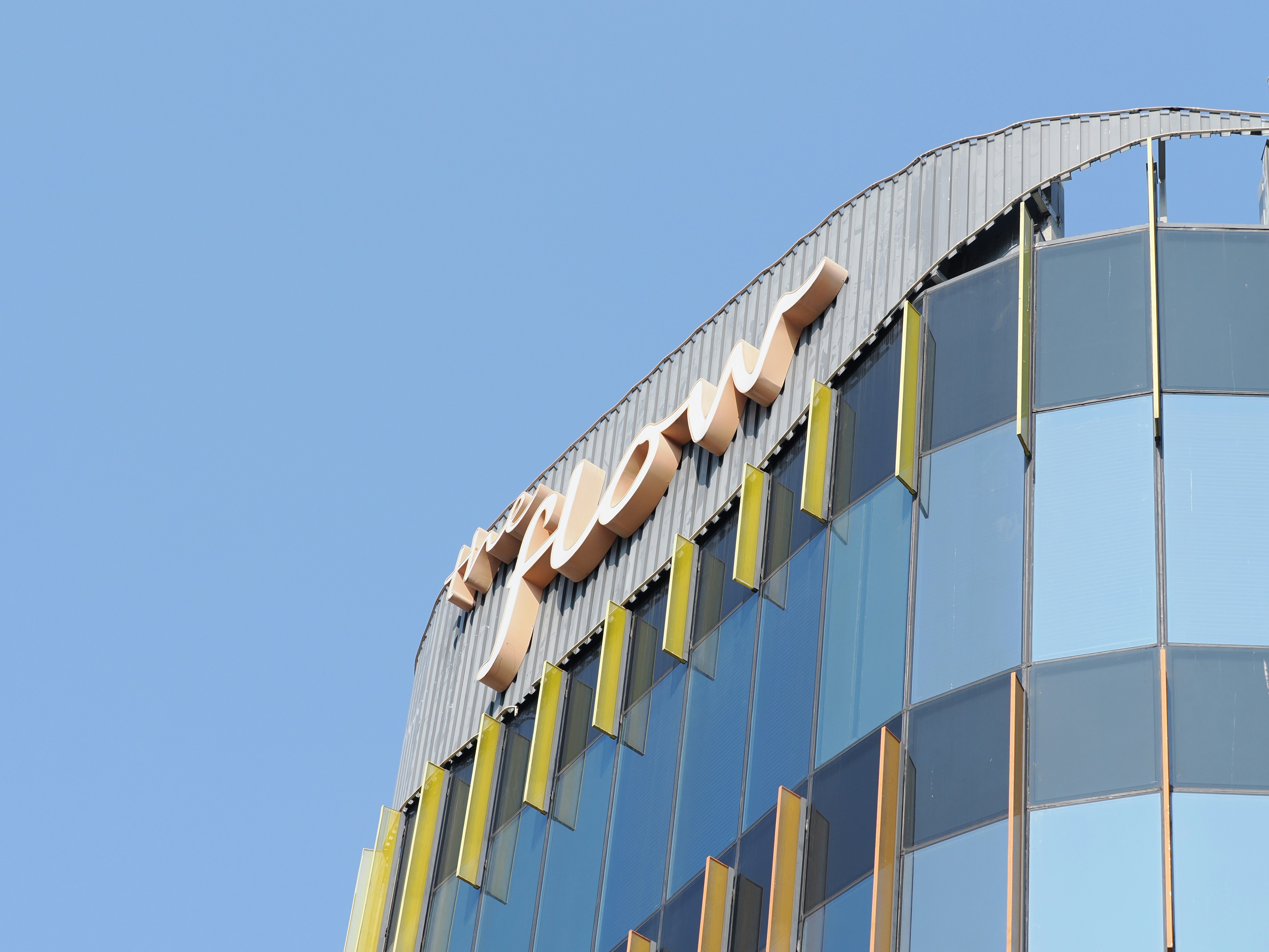 Curved Glass Facade Clad in Blue Panels with Prominent Signage