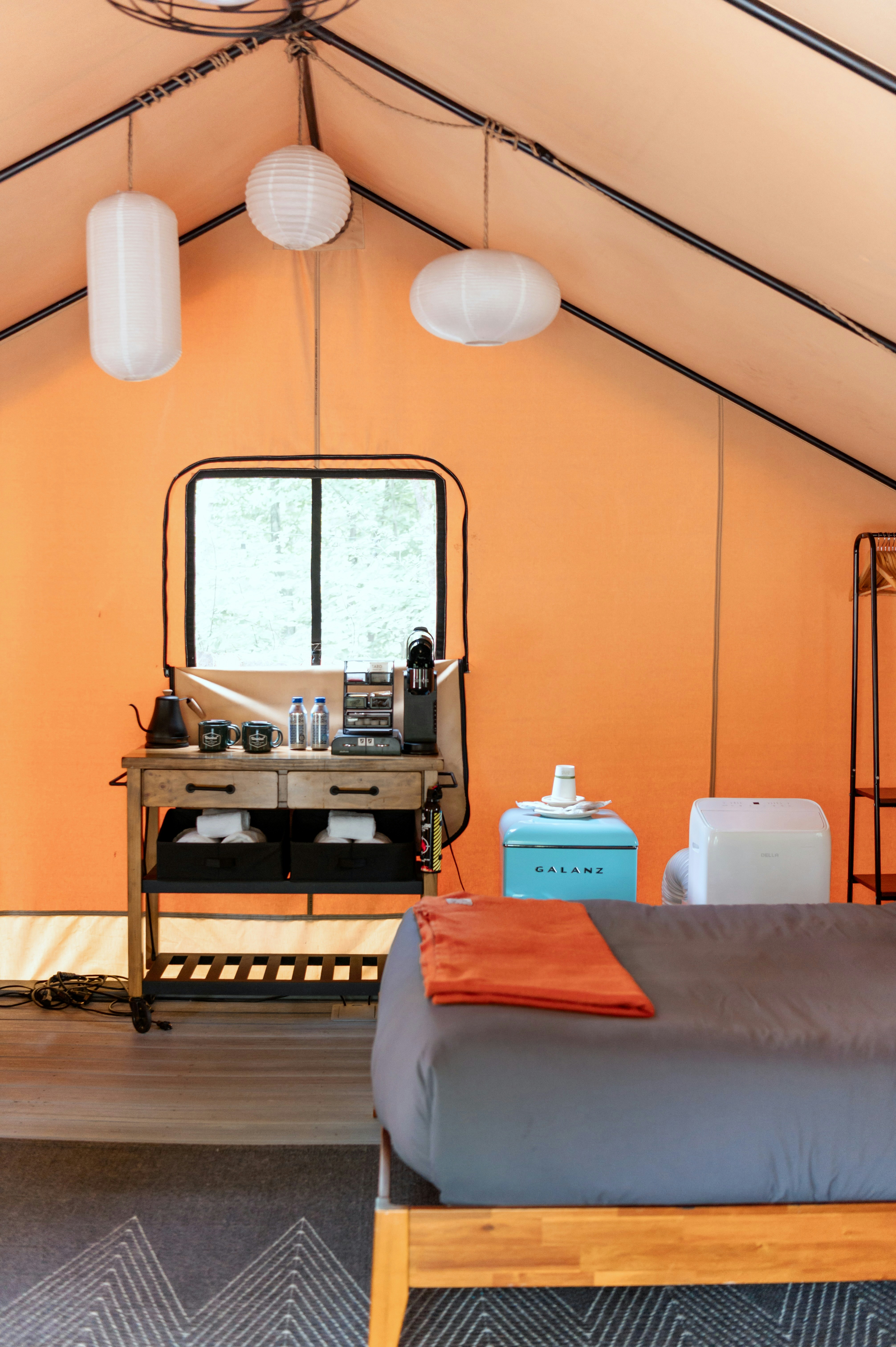 Orange Shelter Studio: A cozy massage tent with a sunlit workbench and neatly arranged essentials