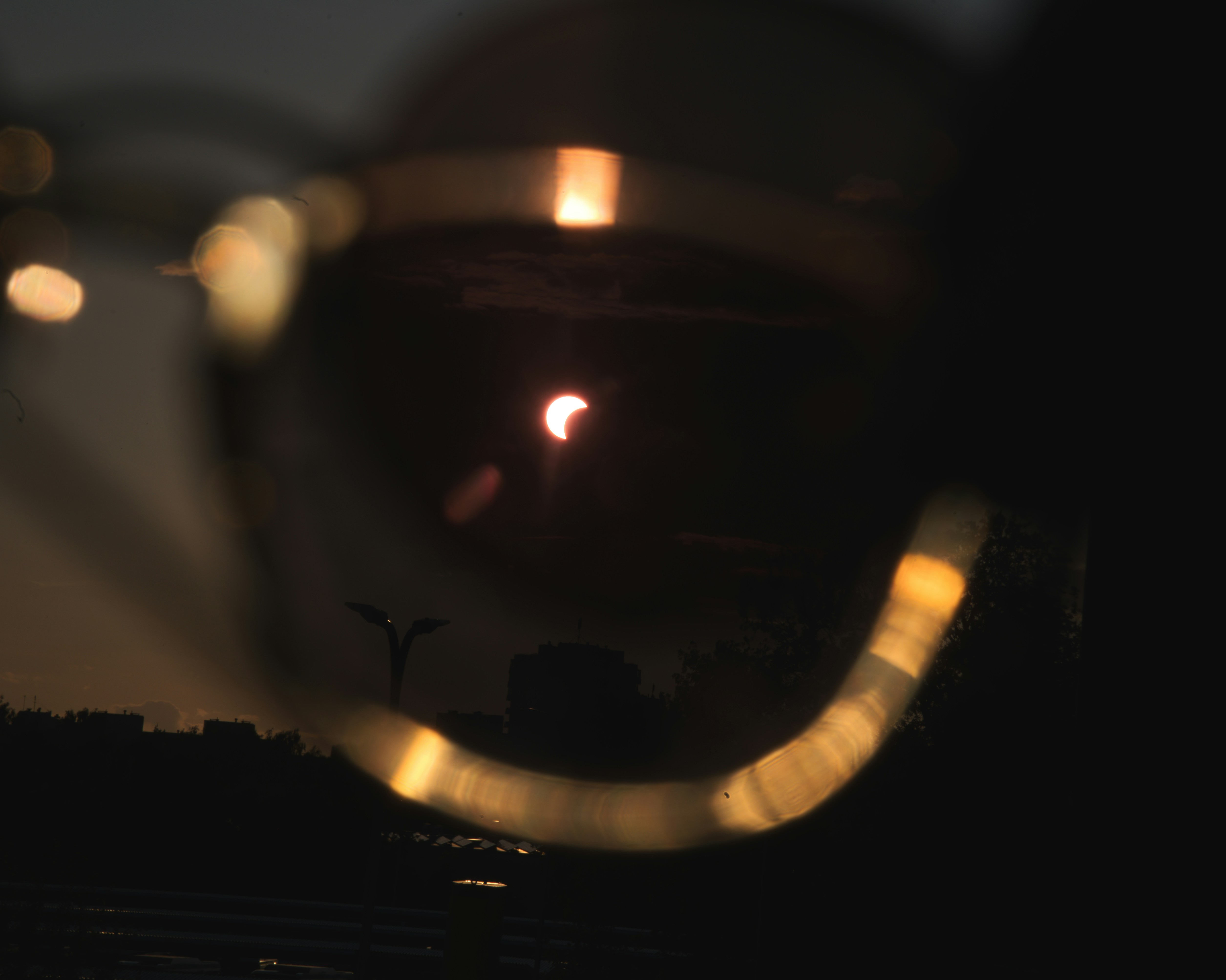 A partial solar eclipse viewed through the circular lens of eyeglasses