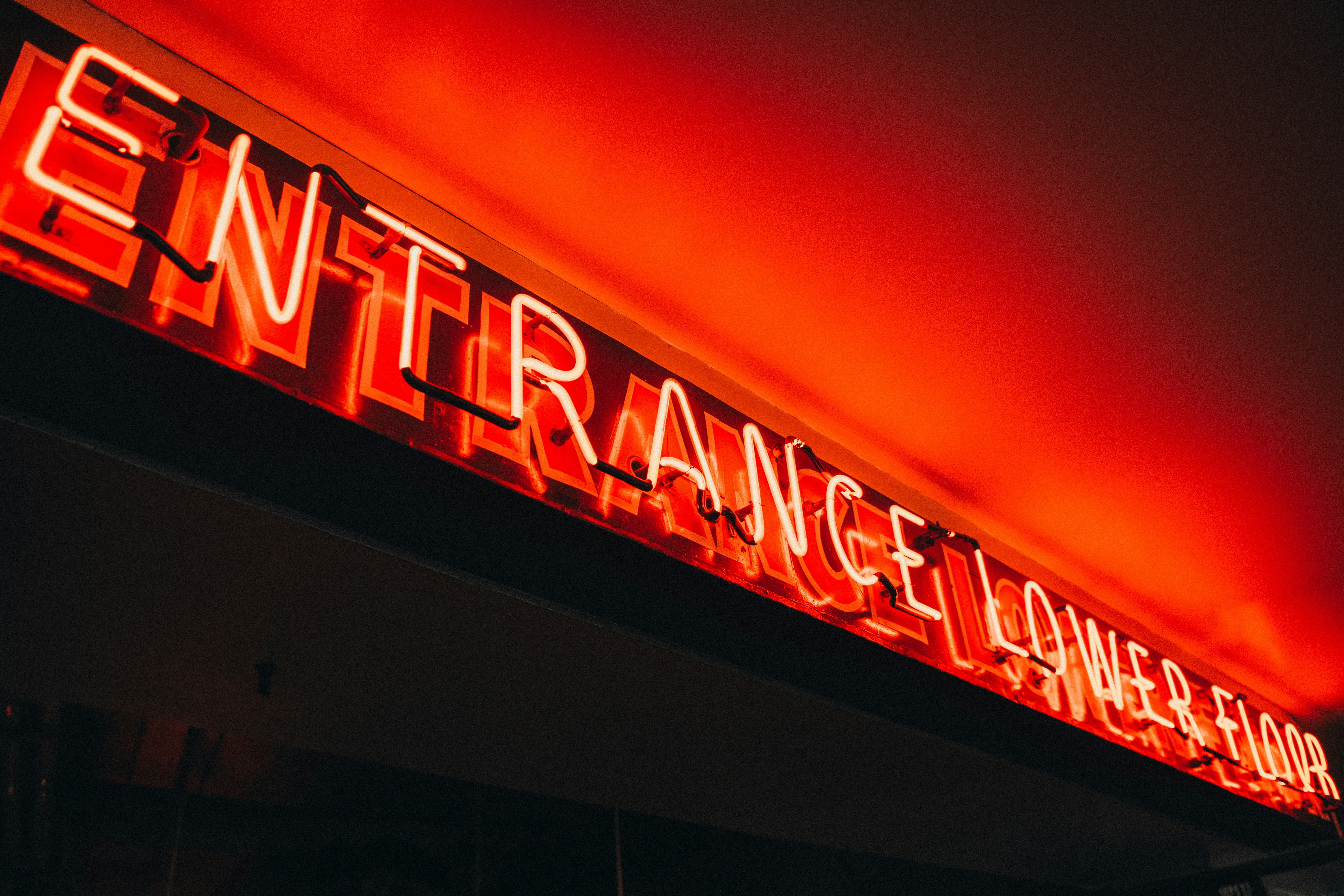 A red neon entrance sign glows inside Pike Place Market in Seattle, Washington, pointing visitors toward the lower floor.