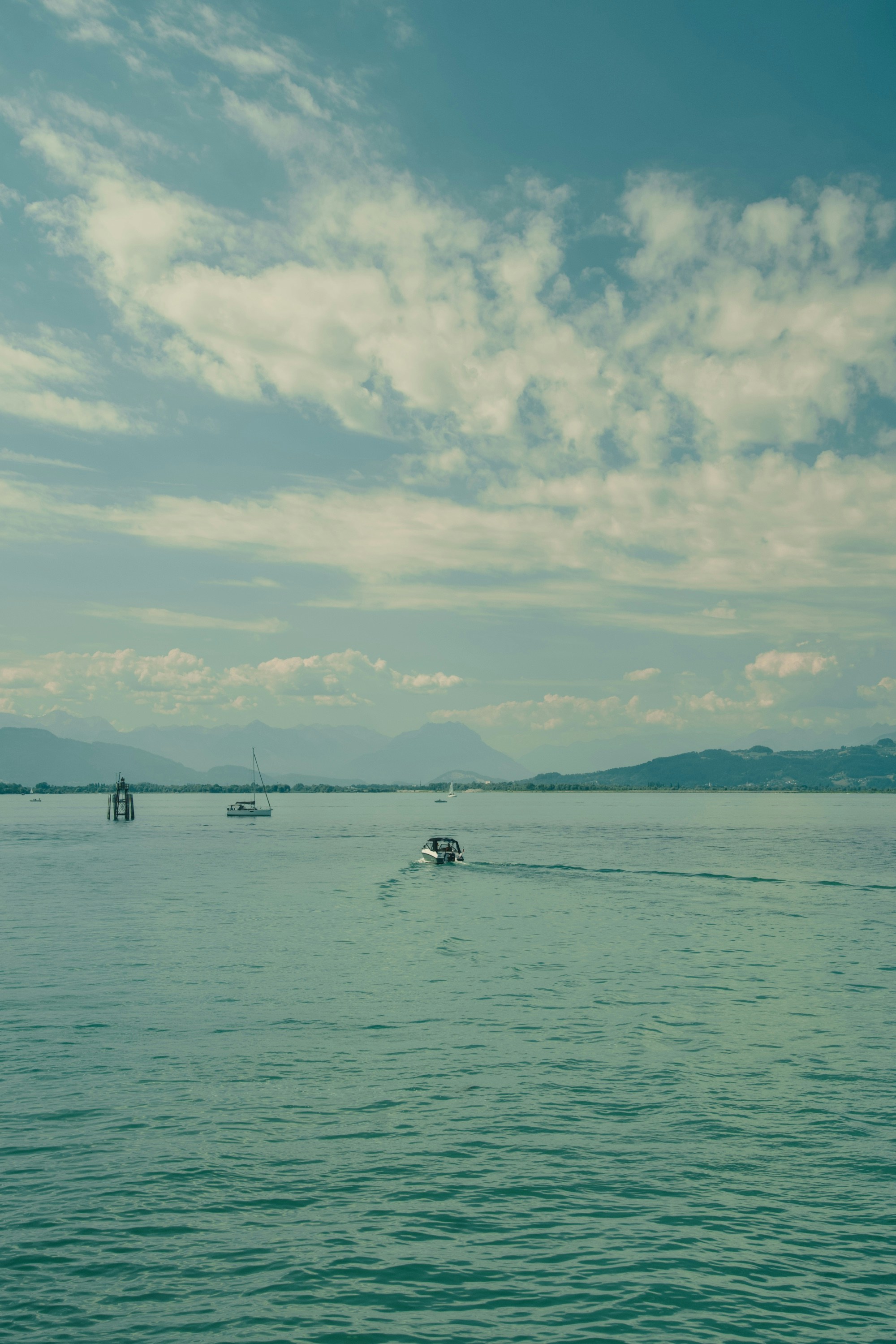 Calm Bay at Dusk: Boats Silhouetted Against Misty Mountains