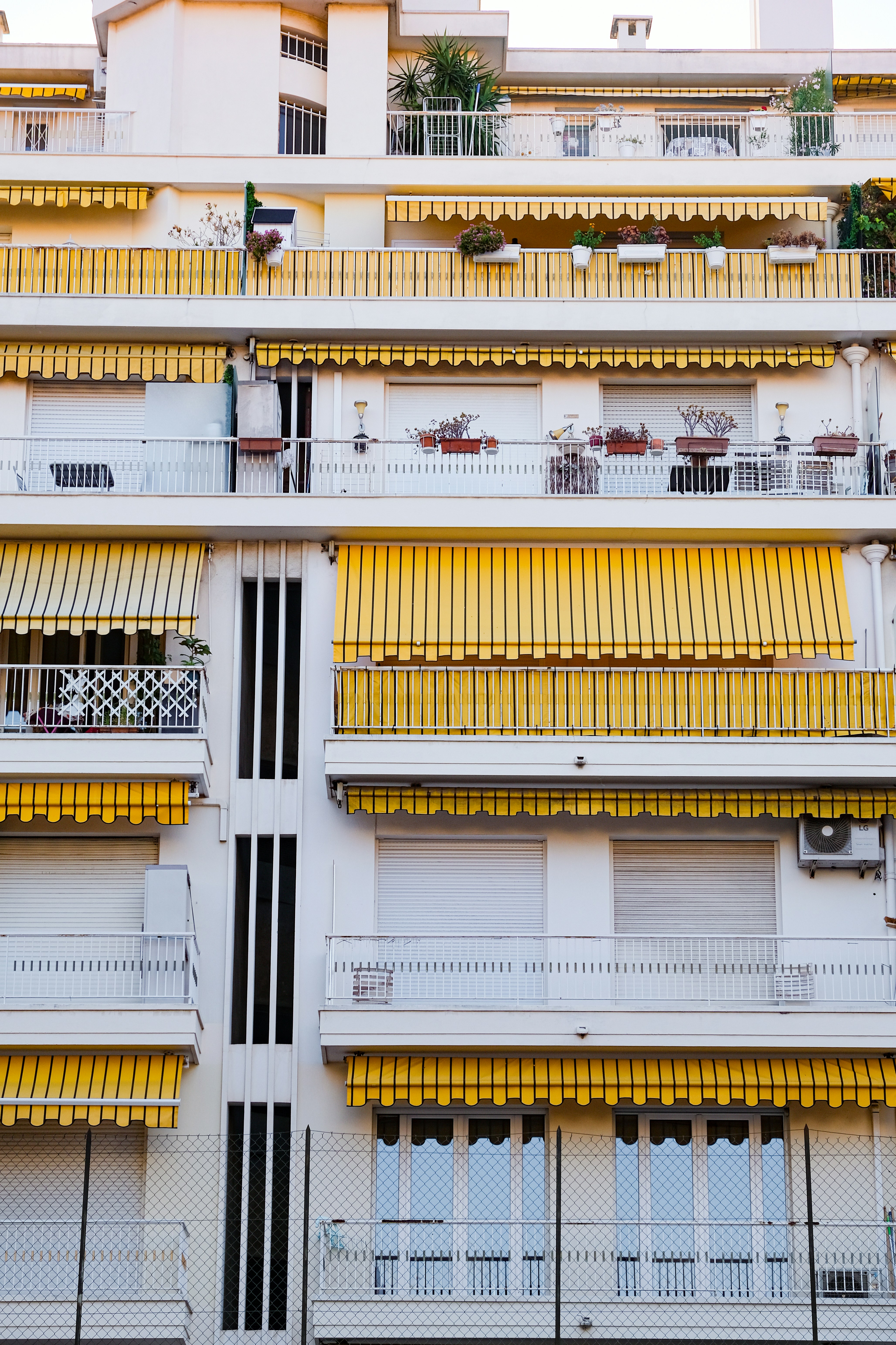 Row of apartment balconies with yellow awnings and railings, forming a geometric urban facade.