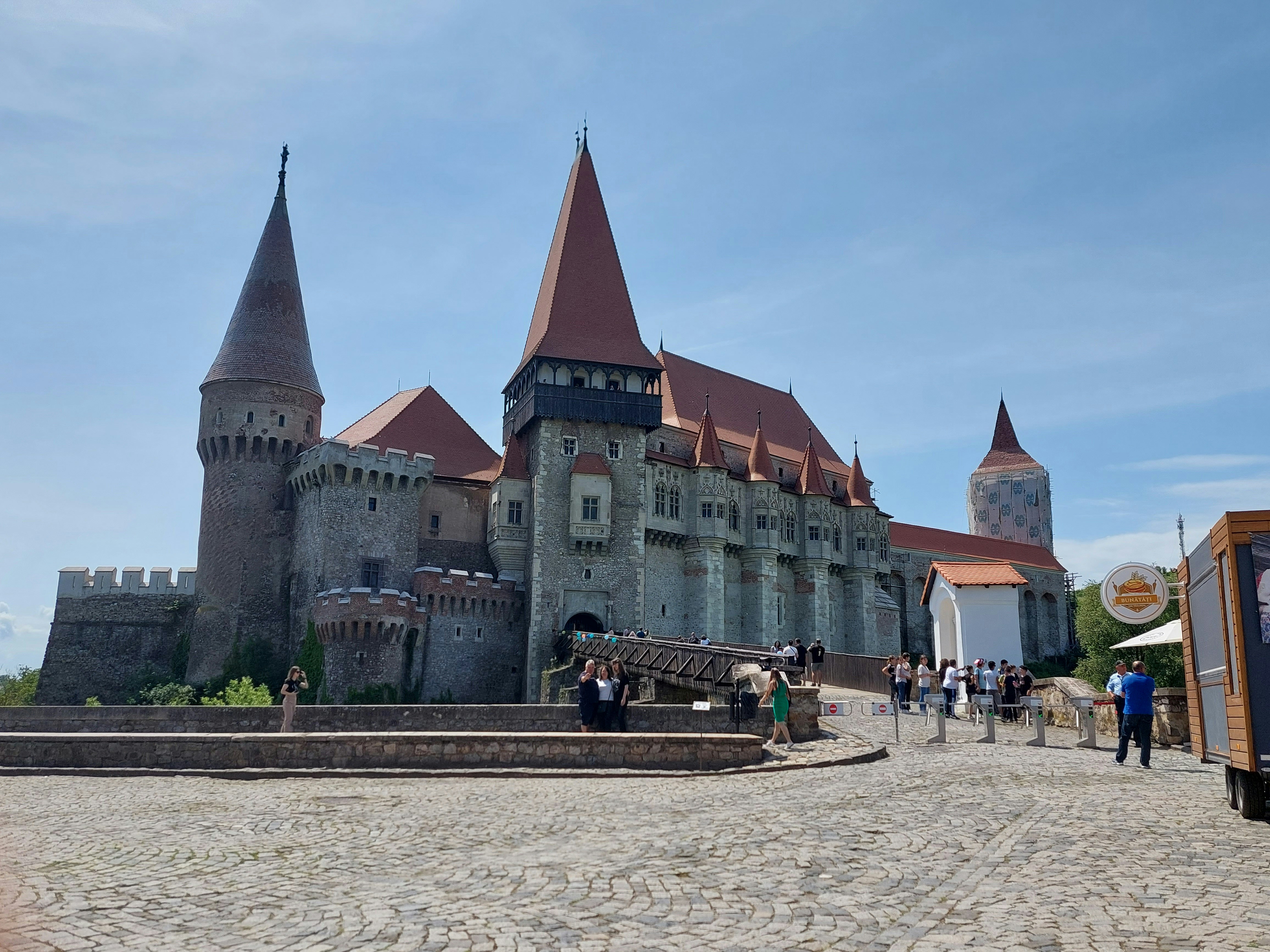 A sunlit medieval fortress rising from a cobbled plaza