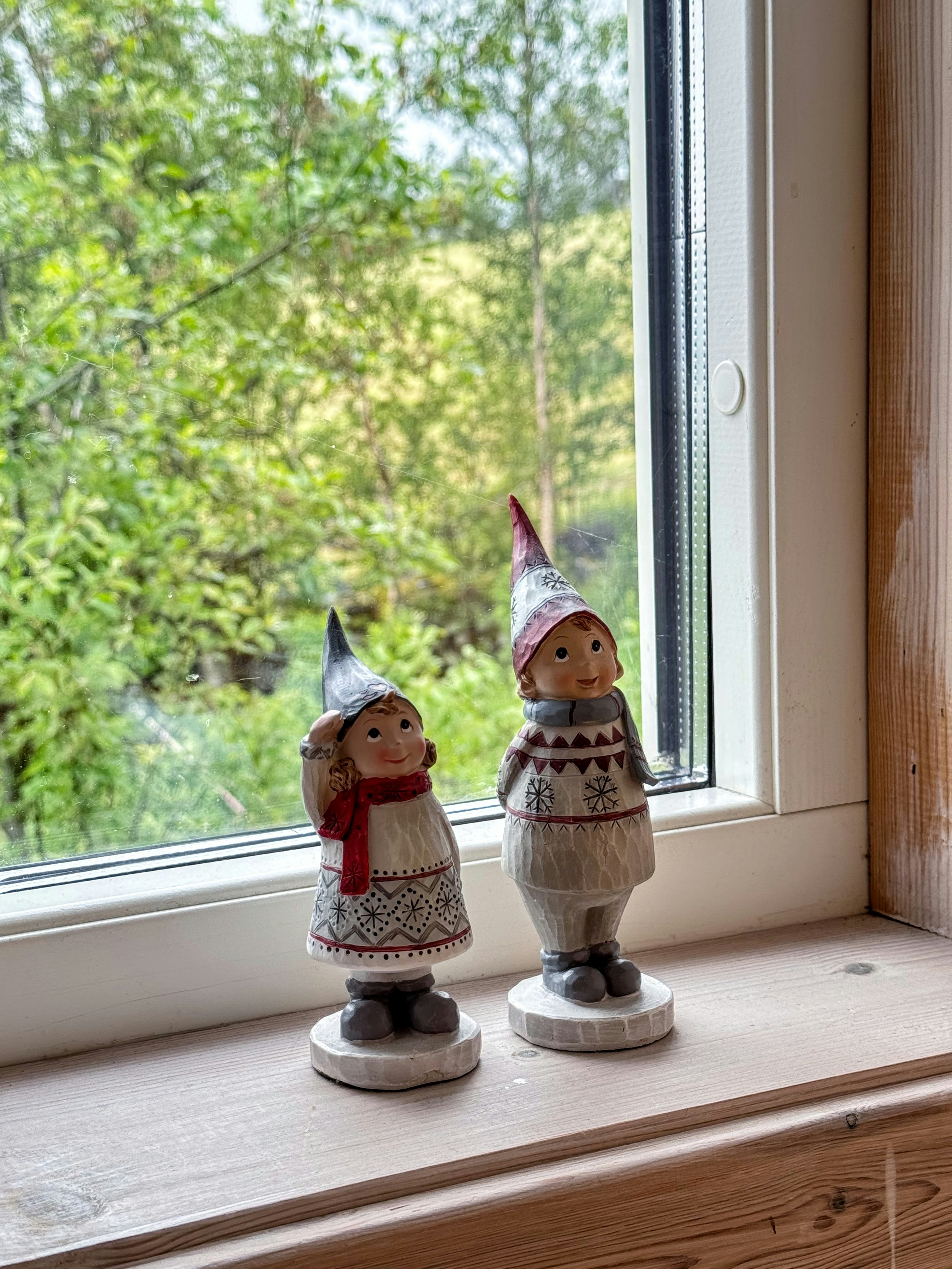 Two Carved Figures Guard the Window's Quiet Green