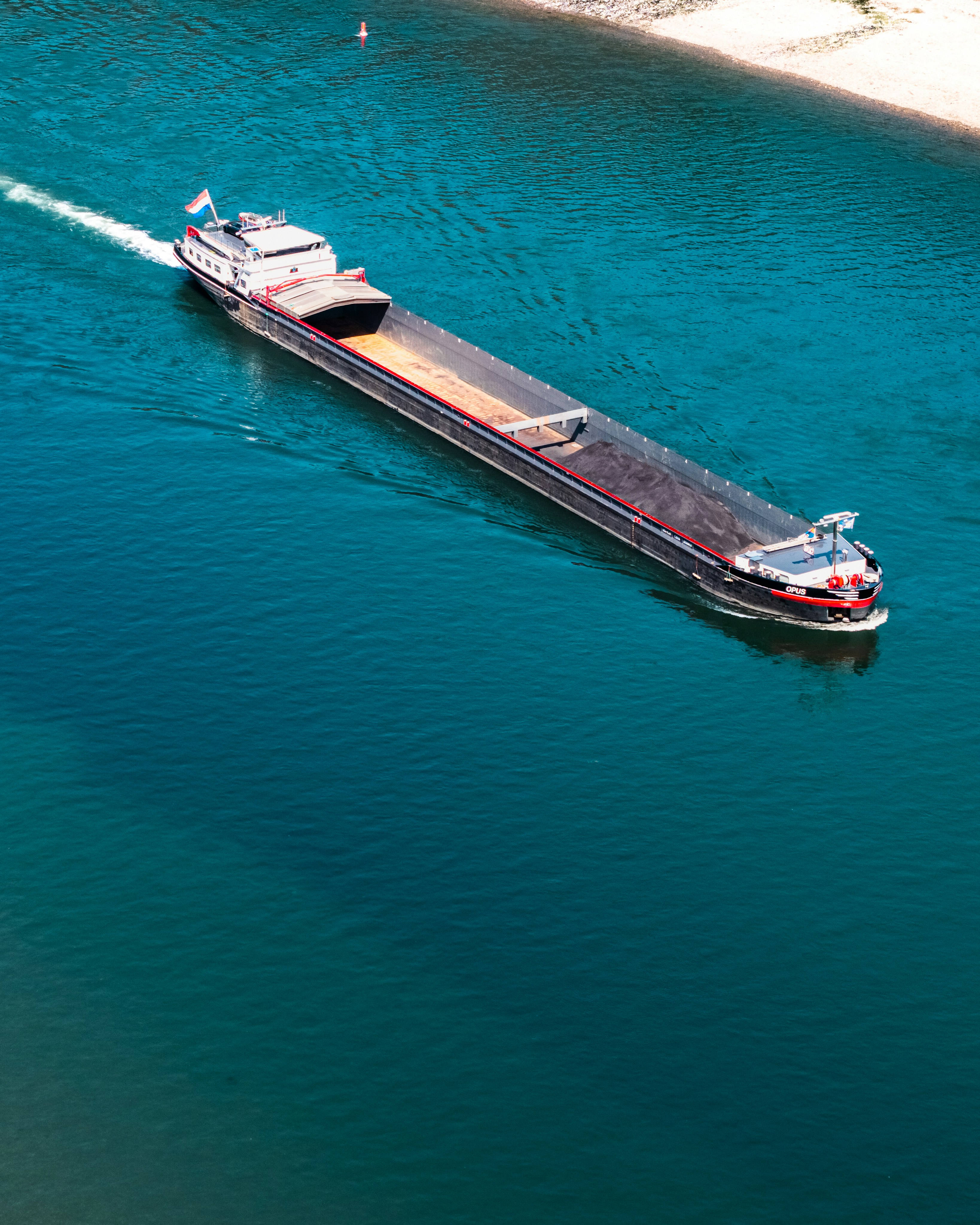 A lone cargo barge gliding through turquoise waters