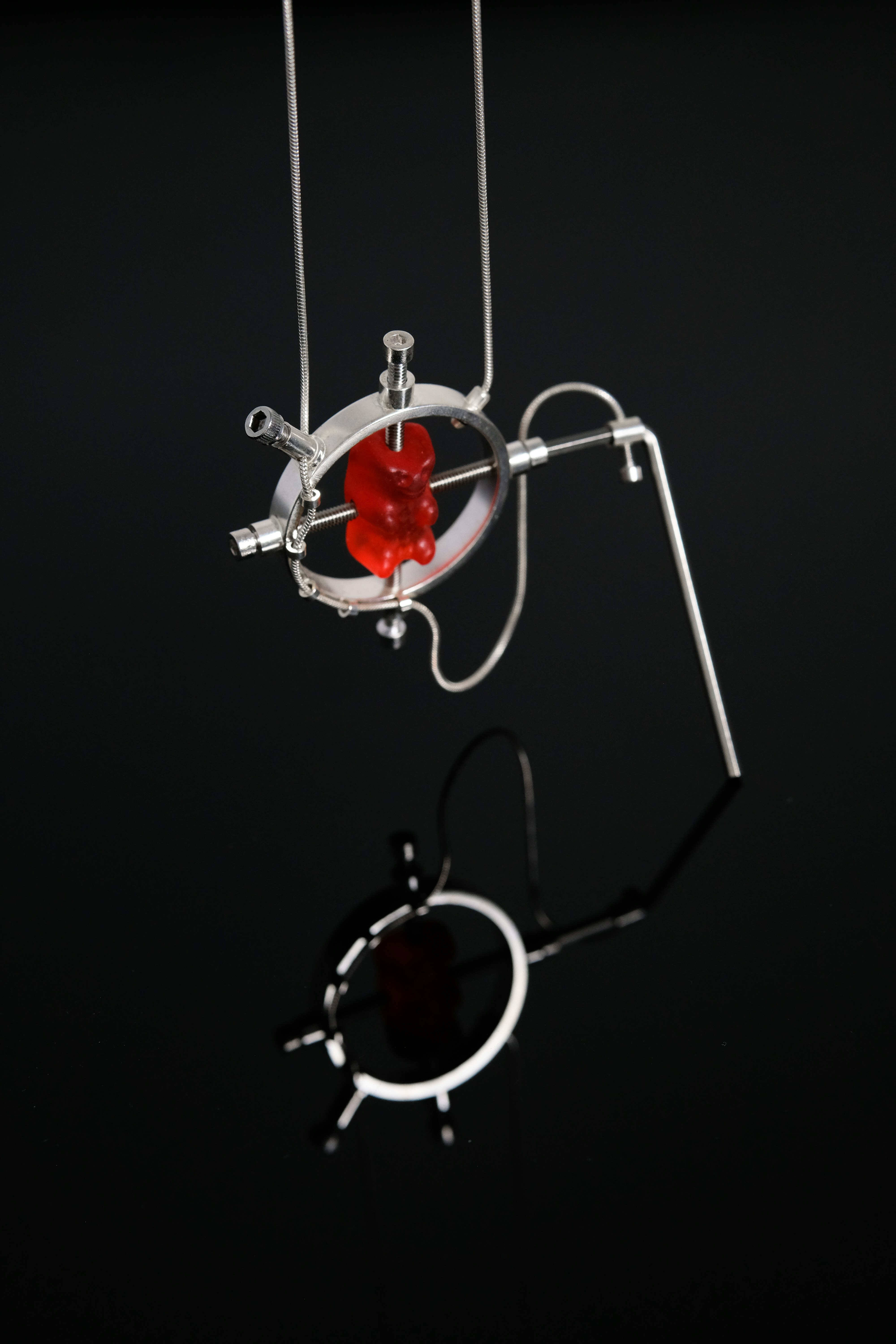Suspended precision: a metrical metal frame and red centerpiece in a black void