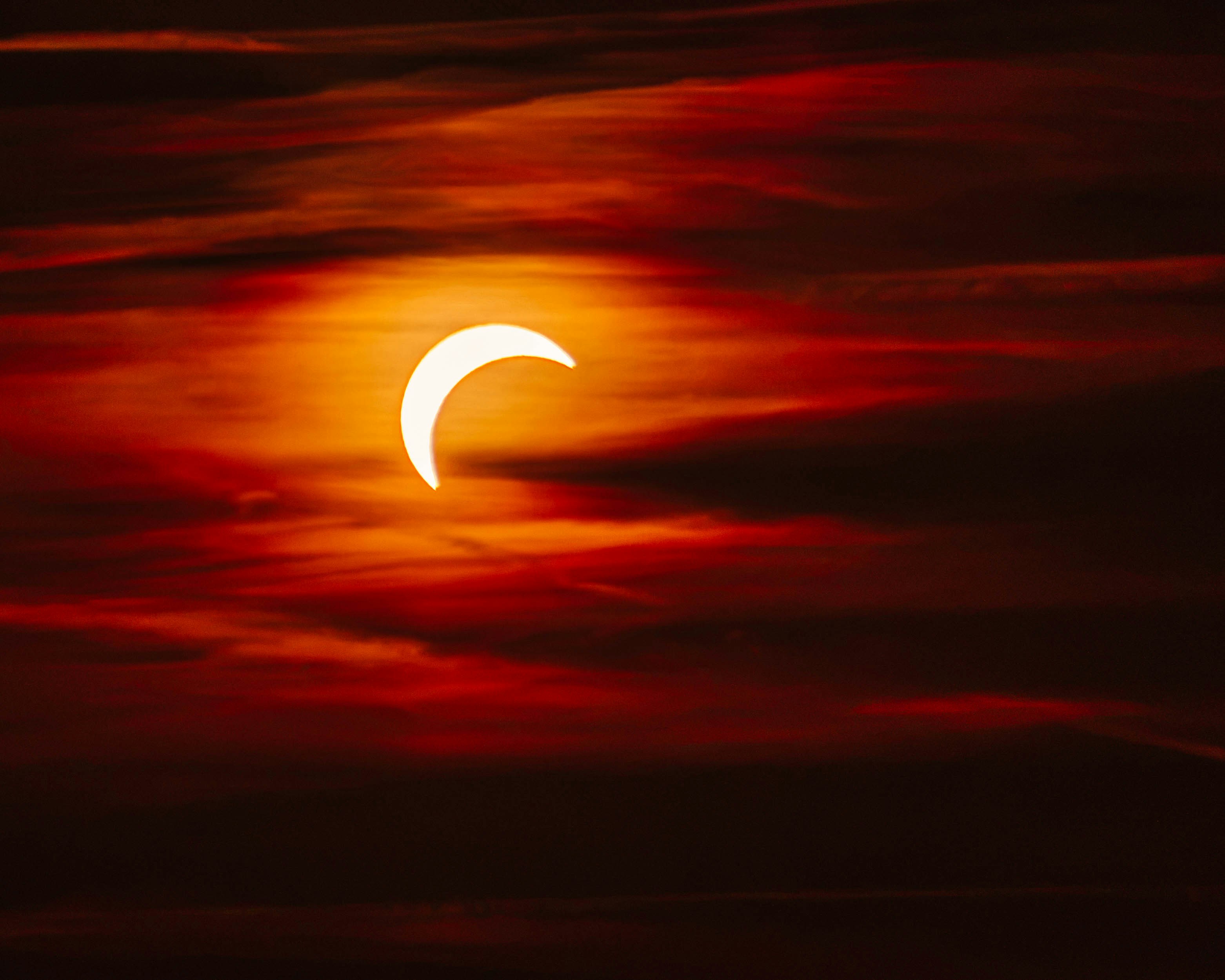 Partial Eclipse of the Sun: A Red-Orange Sky with a Crescent Cutout