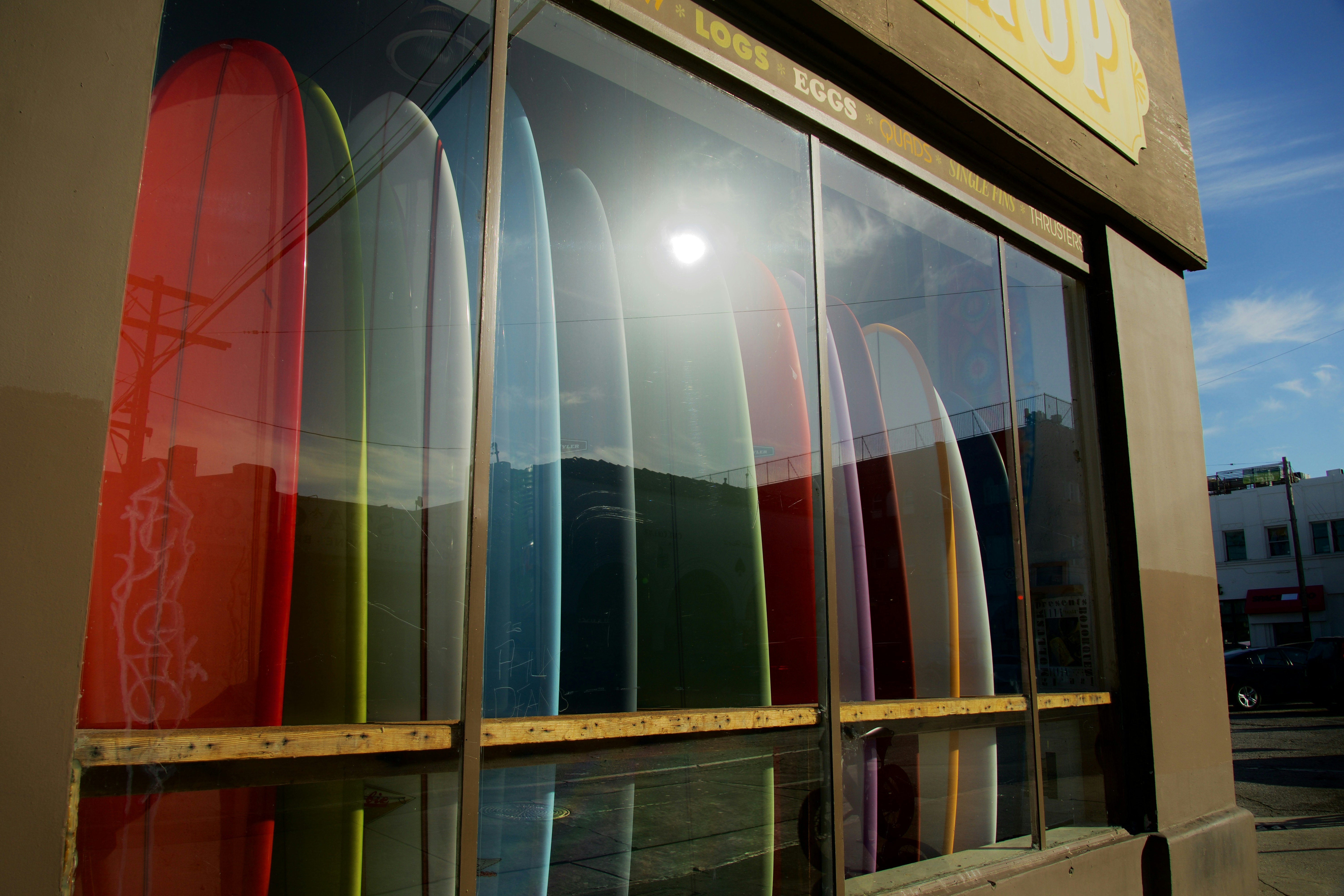 Chromatic Surfboard Windows: Colorful Glass Reflections in a Beachside Shopfront