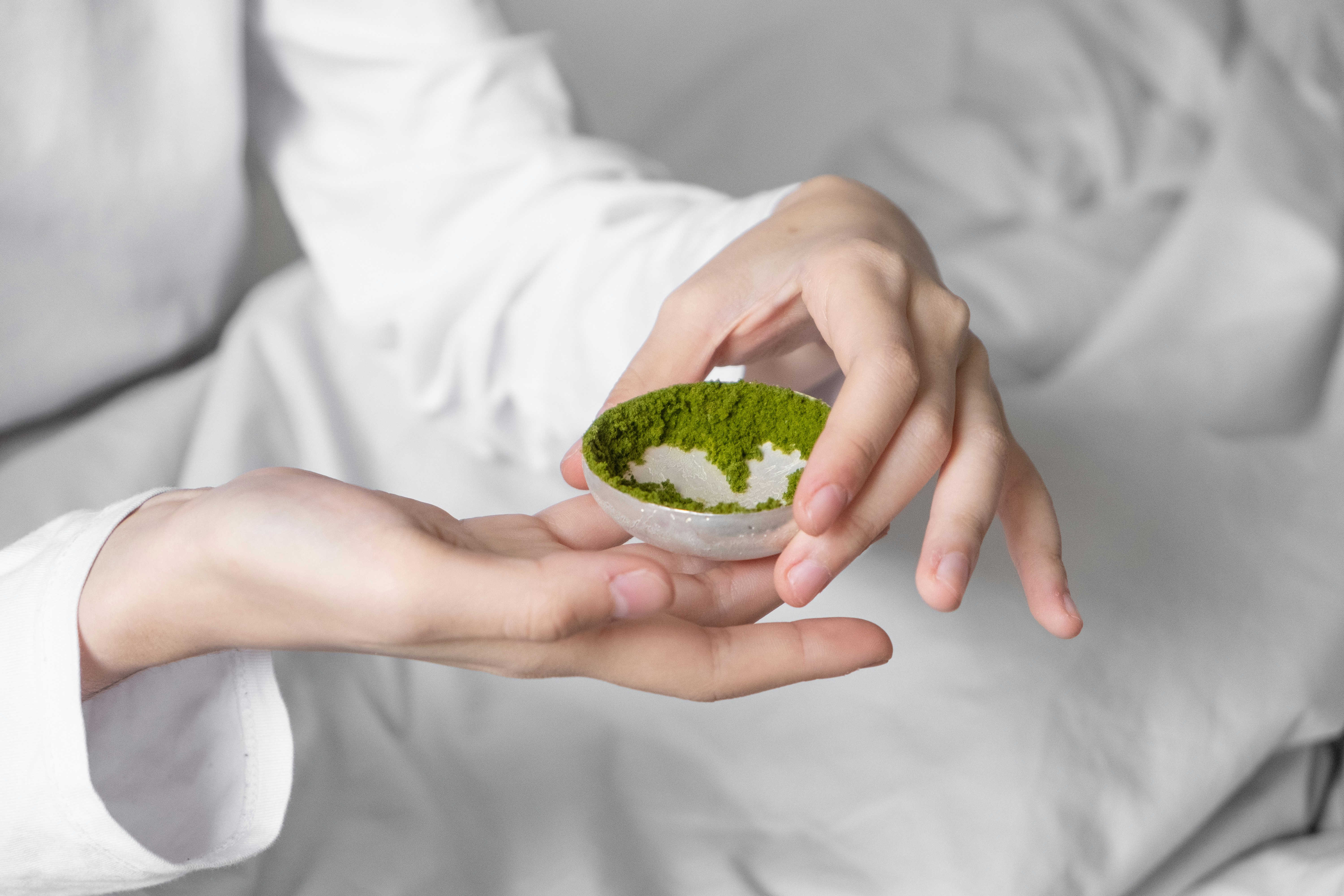 Green Moon in Hand: Delicate Matcha Sphere Between White Robe and Calm Space