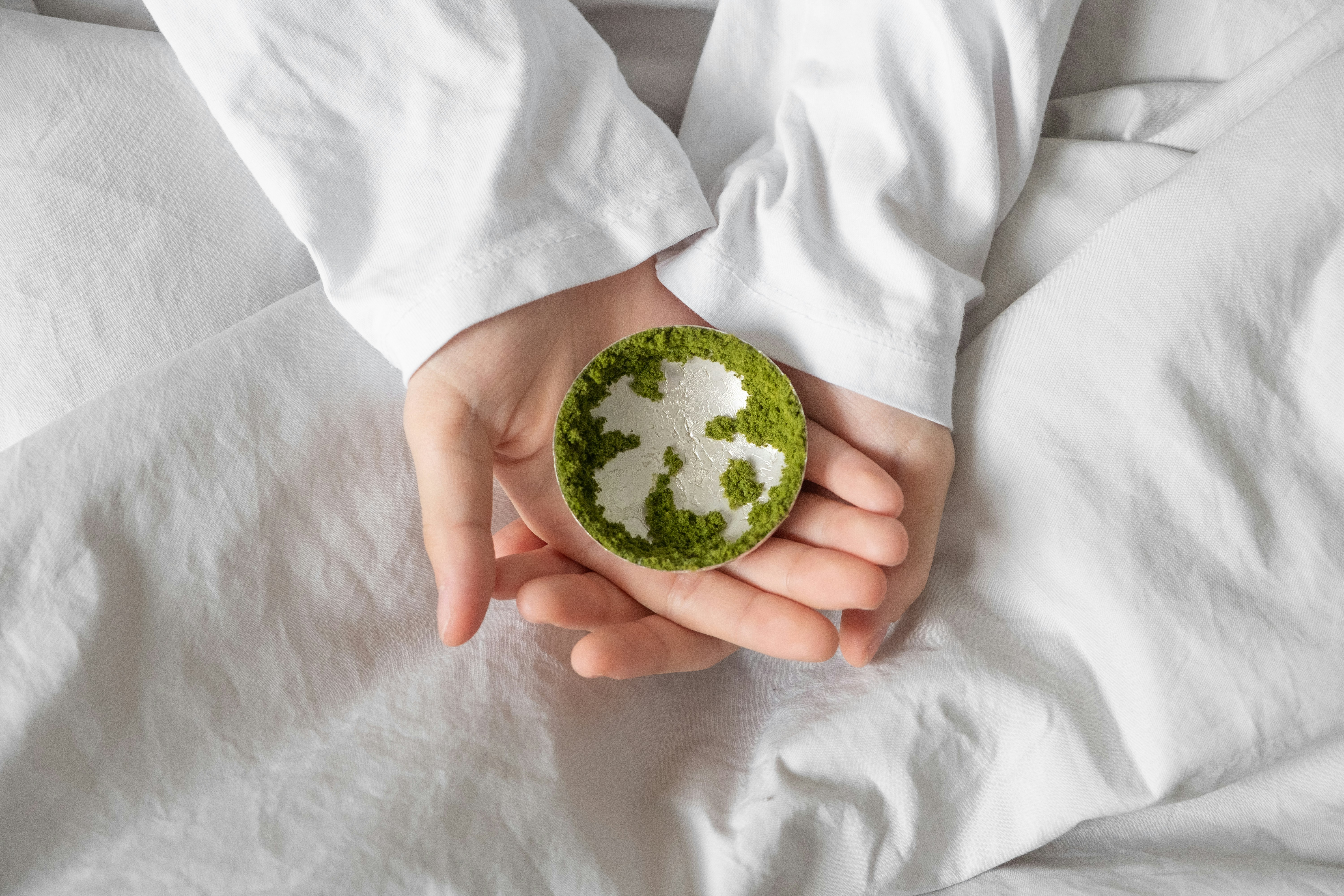 Tiny Green Planet Cradled in White Sheets