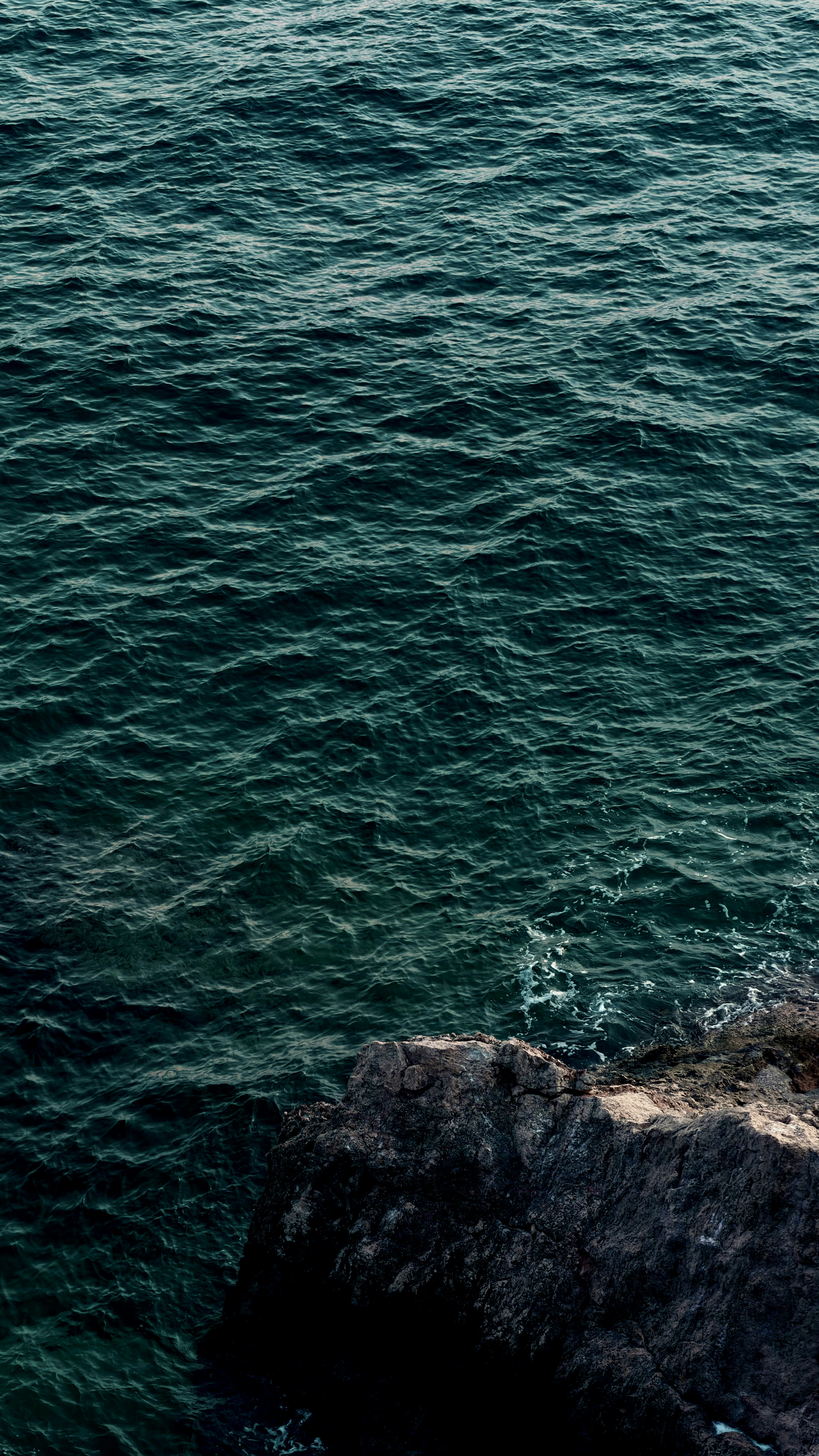 A Lone Coastal Outcrop Edges into Deep Teal Waters