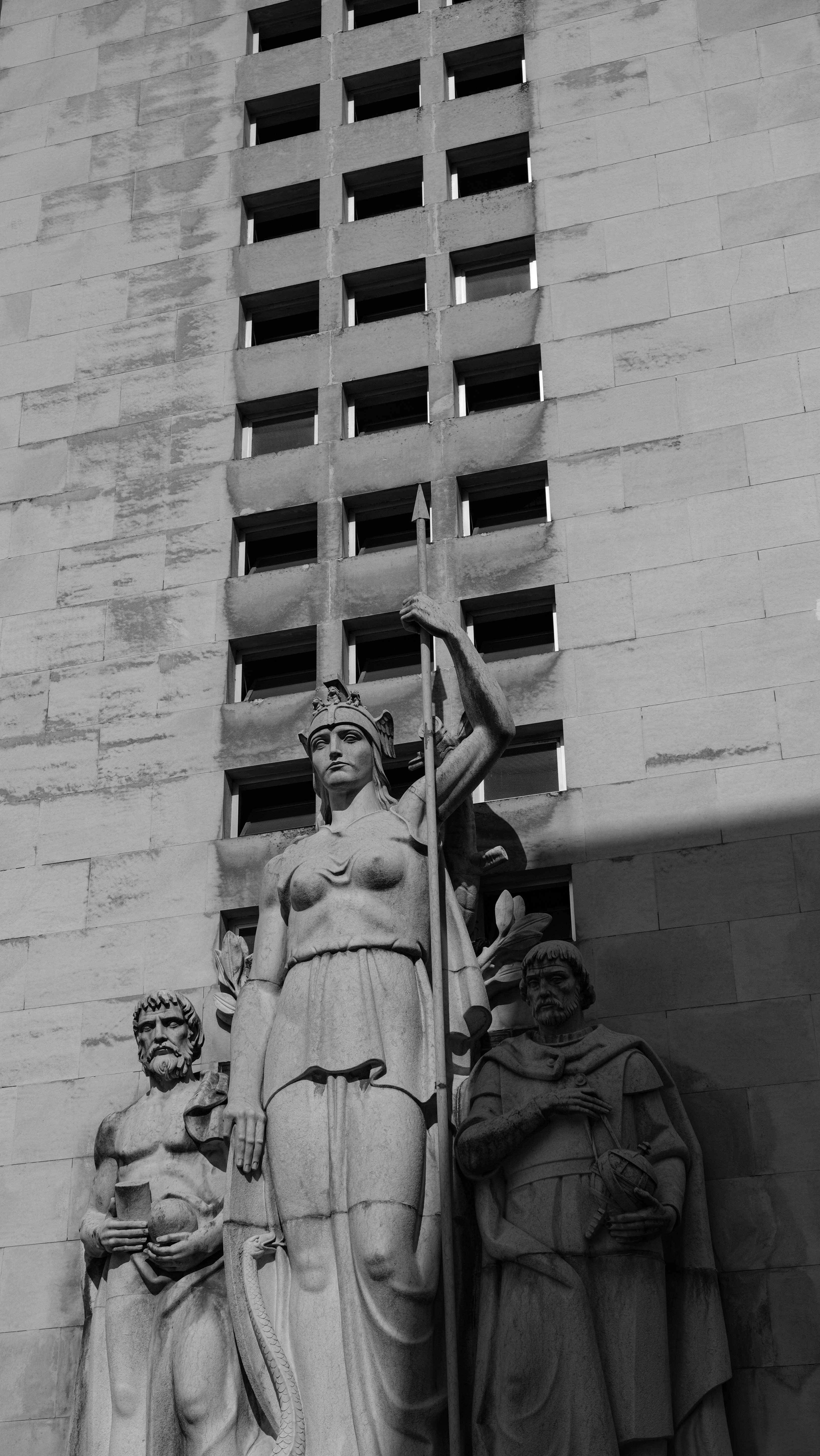 Statuary Vigil: A Monumental Parade of Figures Against a Grid of Windows