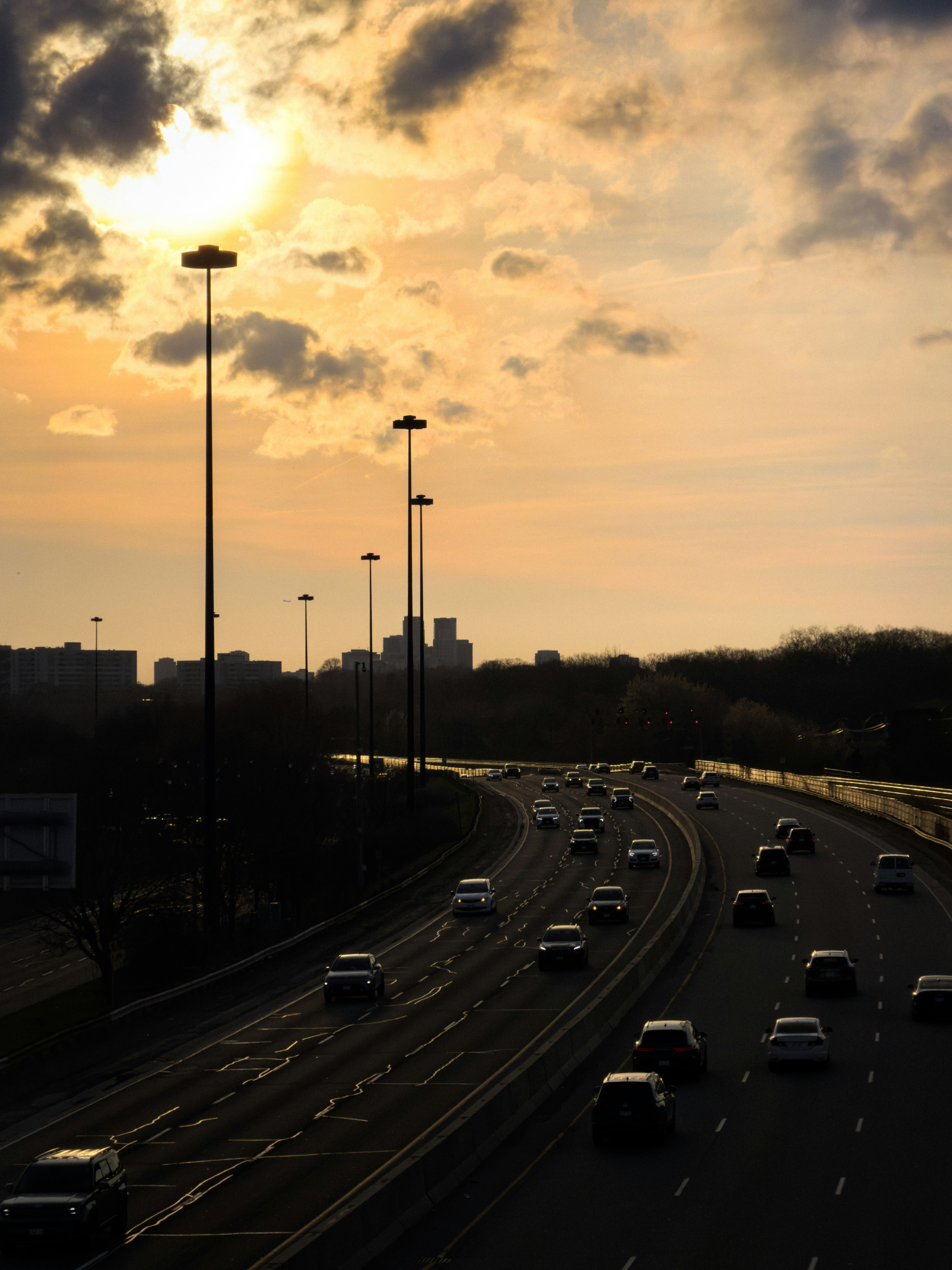 Golden Hour Freeway: Cars in Silhouette Under a Looming Sunset