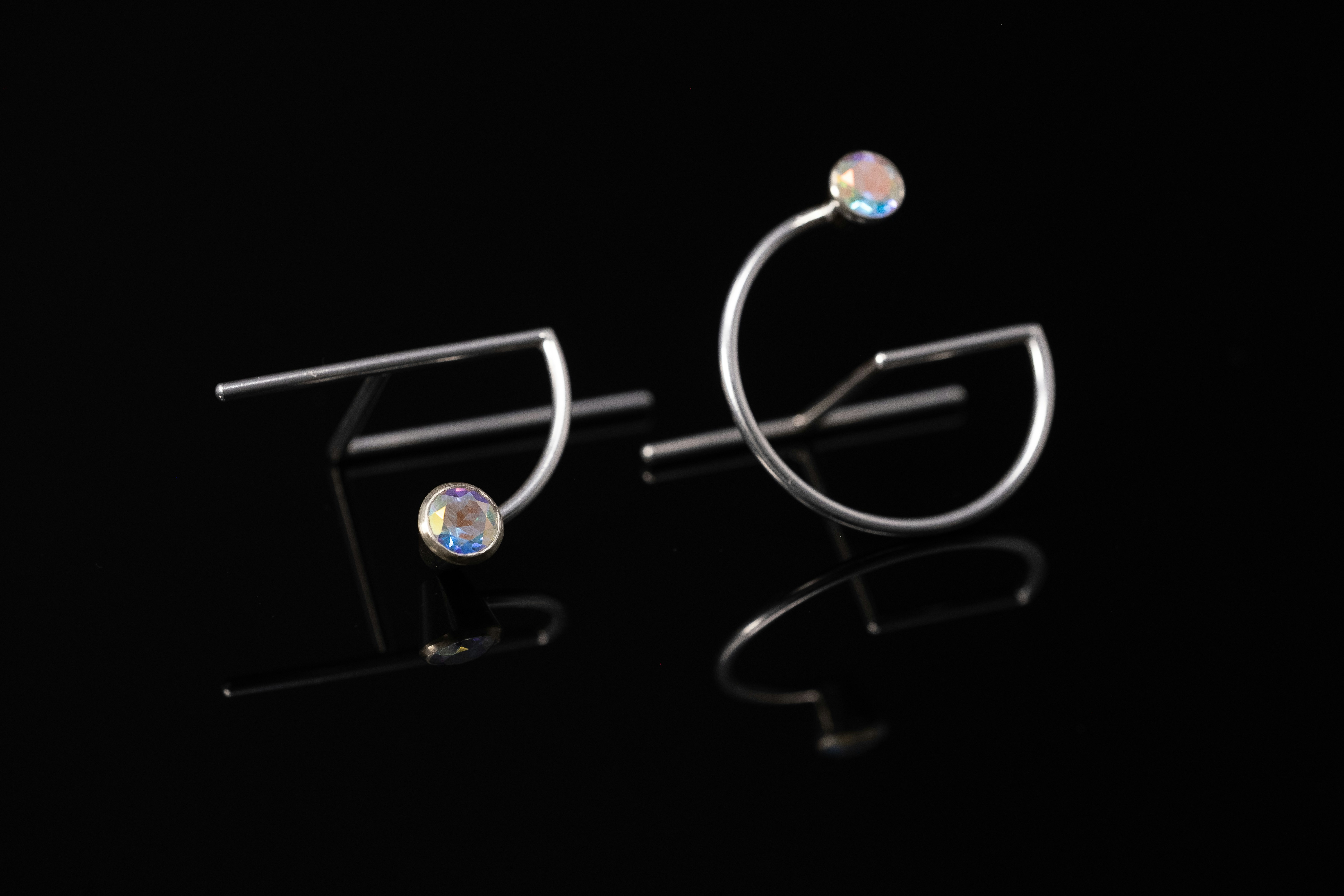 Curved silver accents: minimalist earrings on a glassy stage