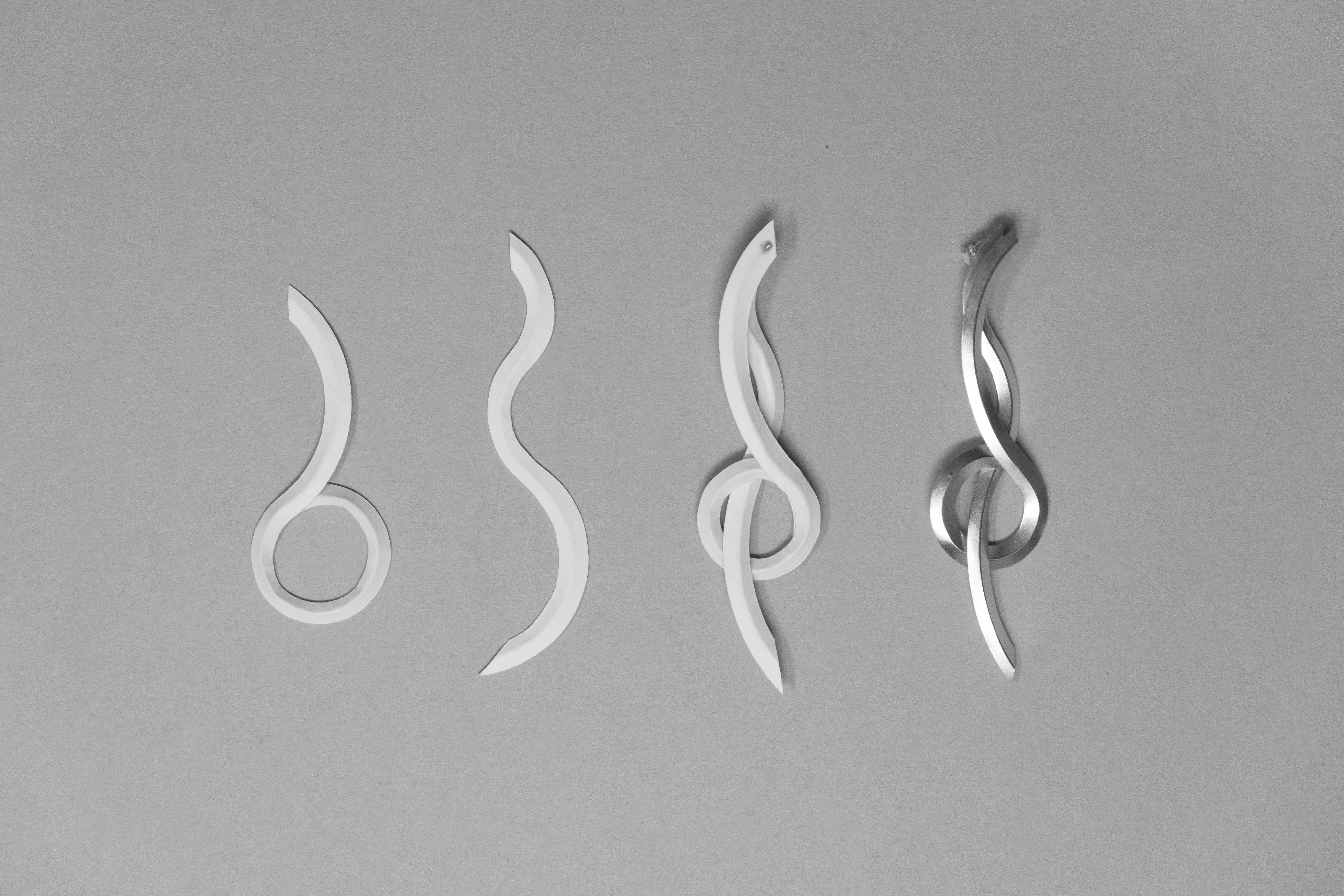 Metal loops arranged in a row, showing a progression from simple to more complex shapes on a plain backdrop.