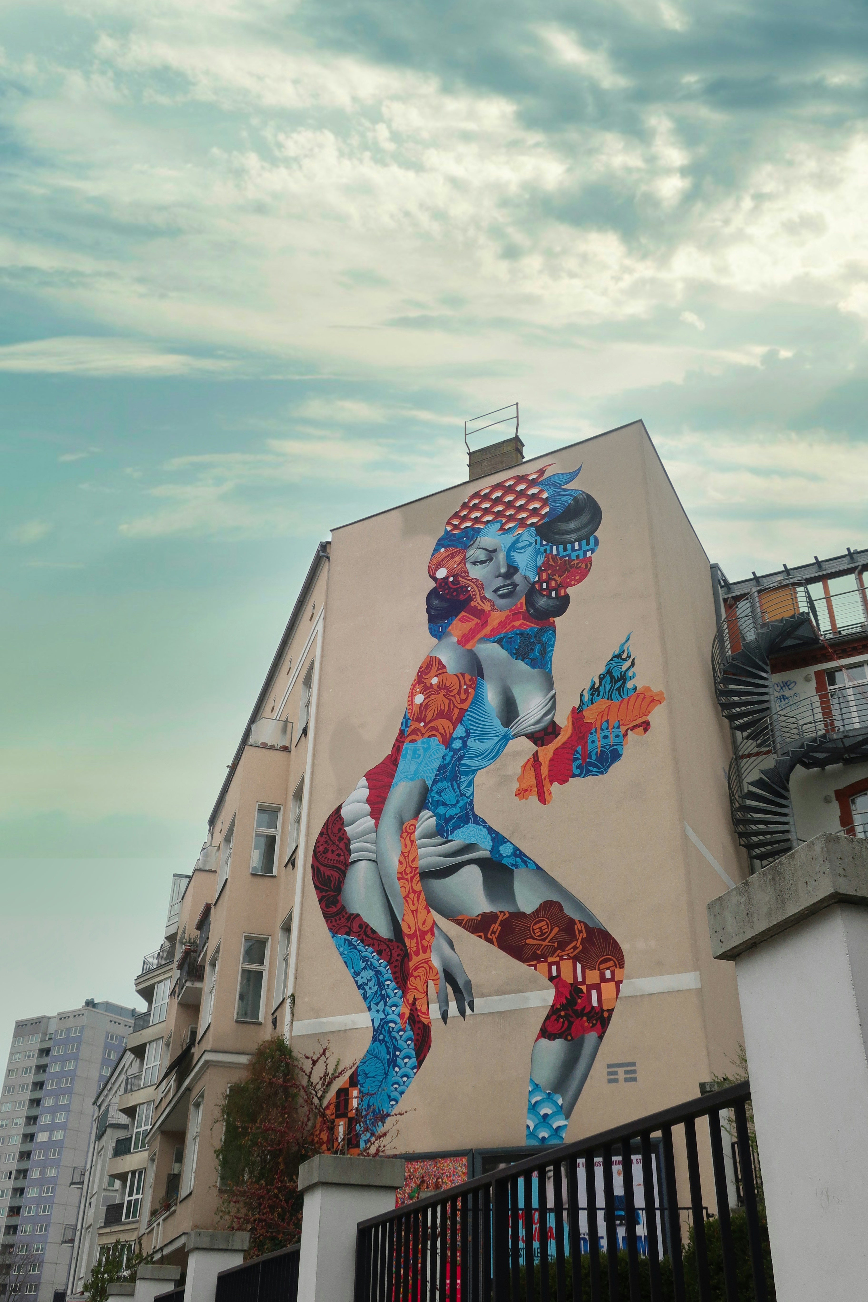 Street mural skyscape: a towering figure on a sunlit brick facade