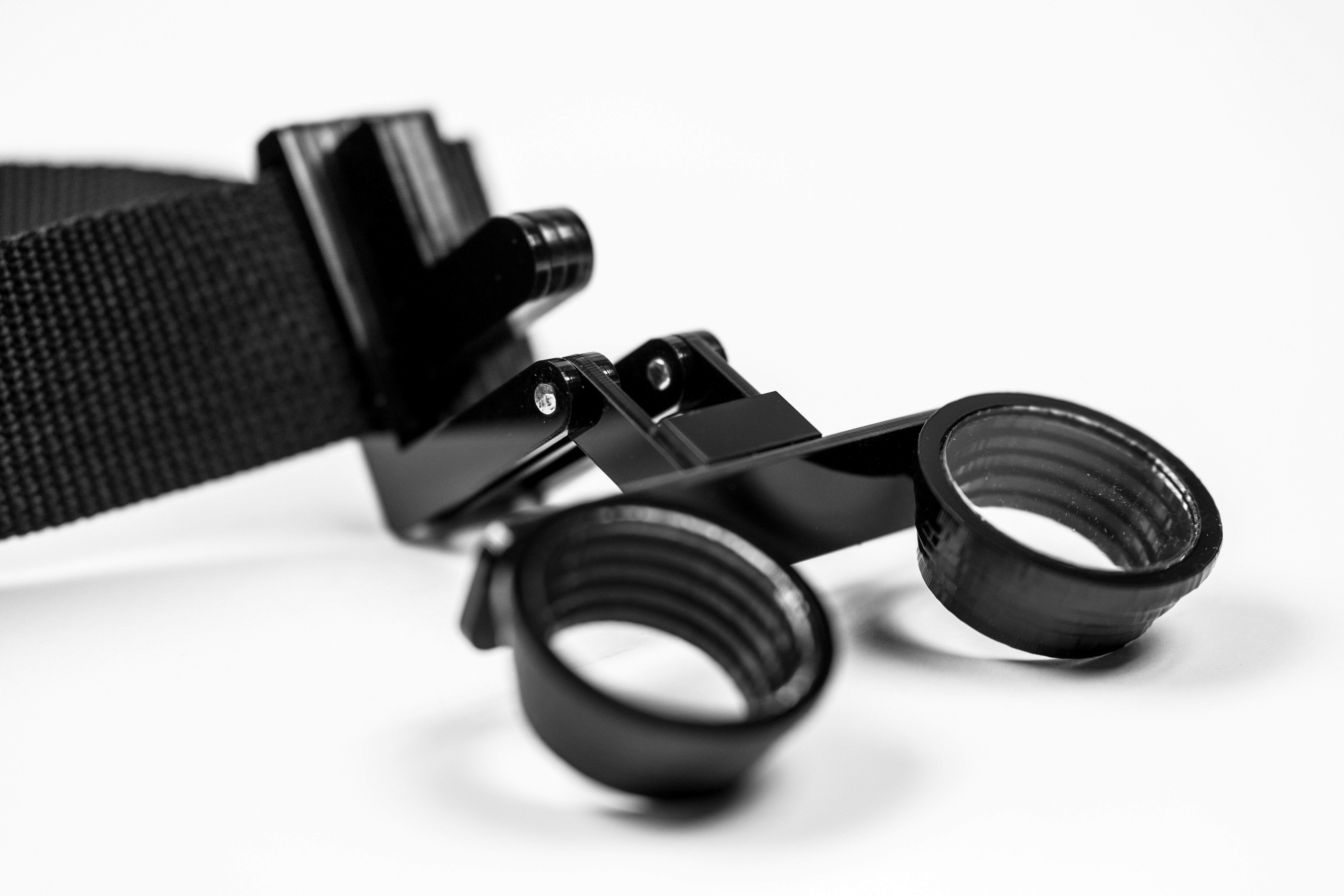 Close-up of a camera strap's quick-release clamps and buckle hardware on a clean white background.