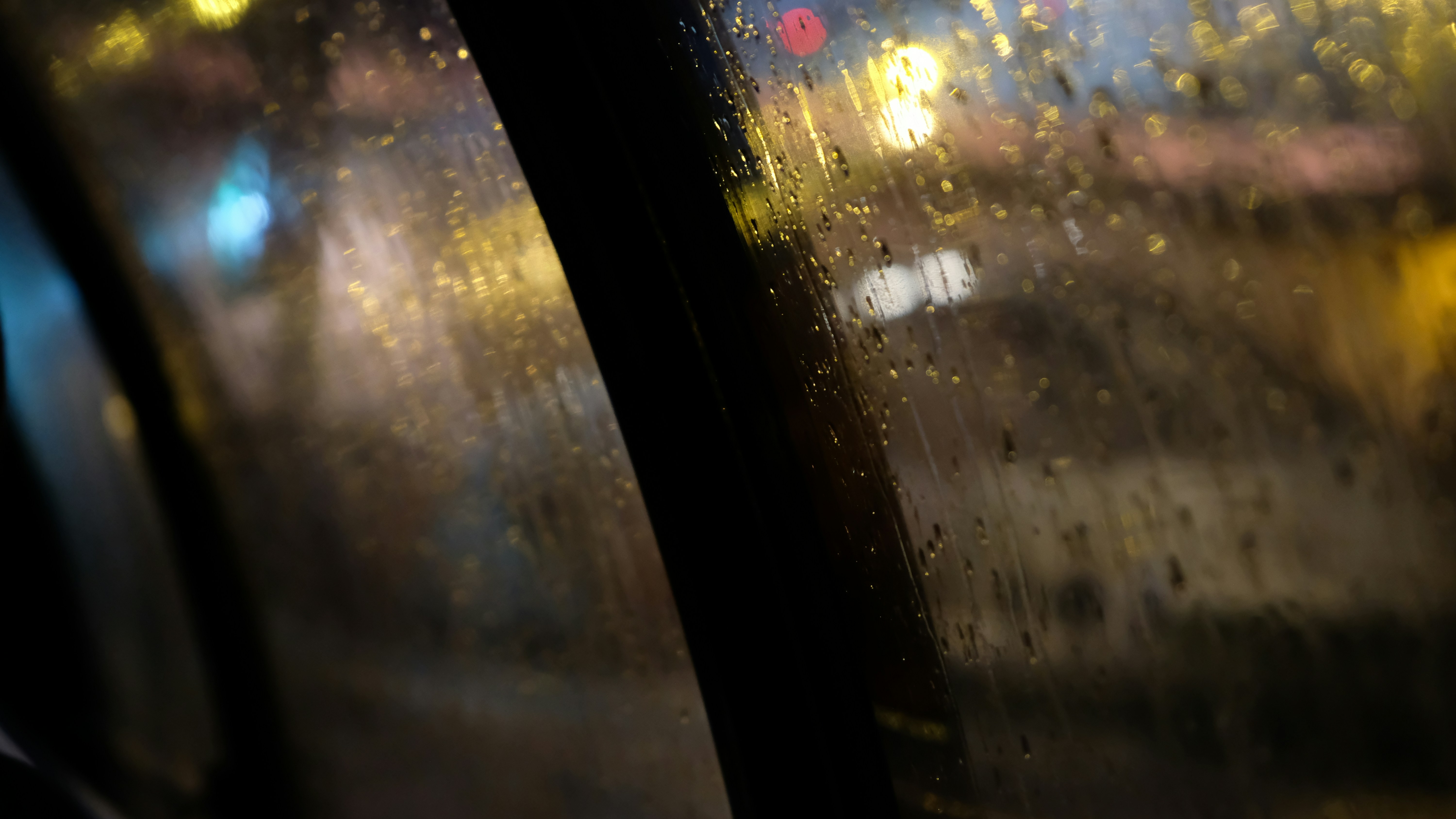 Rain-kissed bus window refracts city lights into moody whispers