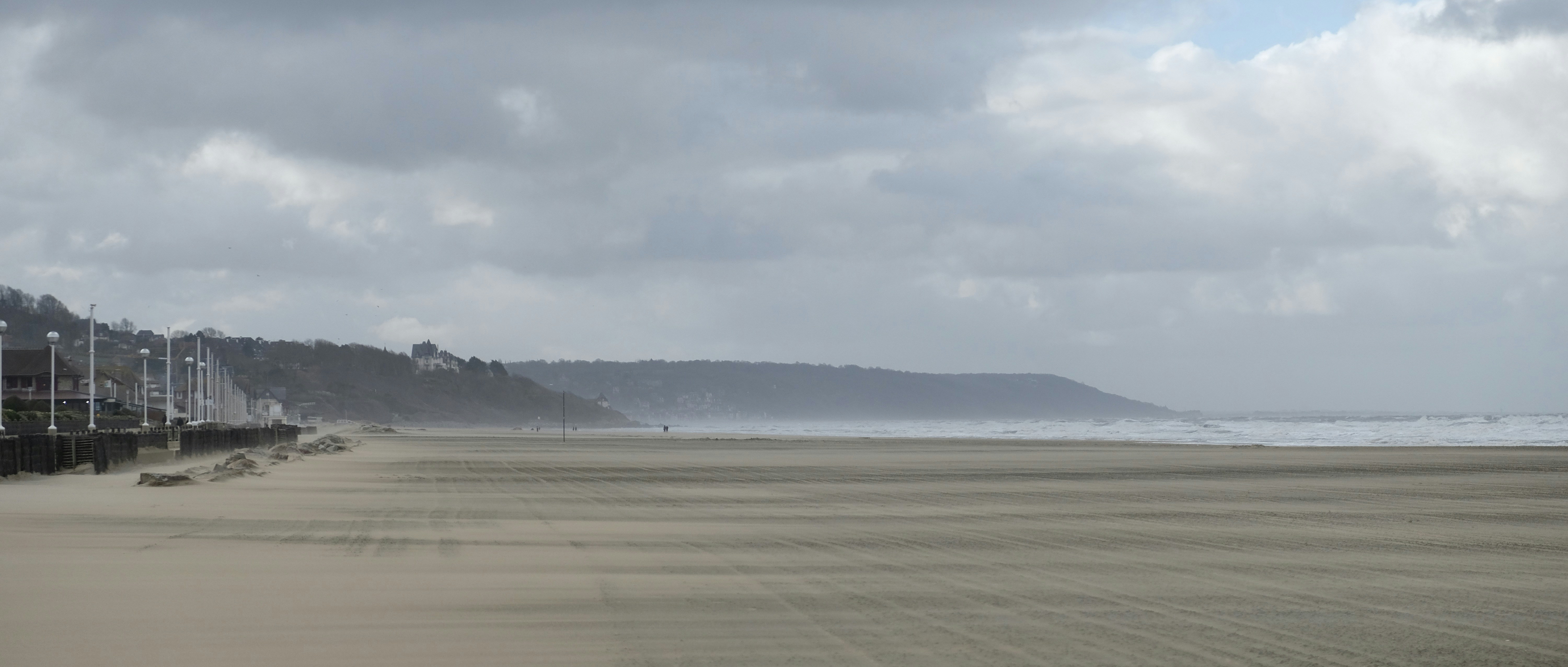 Quiet Dunes and Distant Promenade Under Overcast Sky