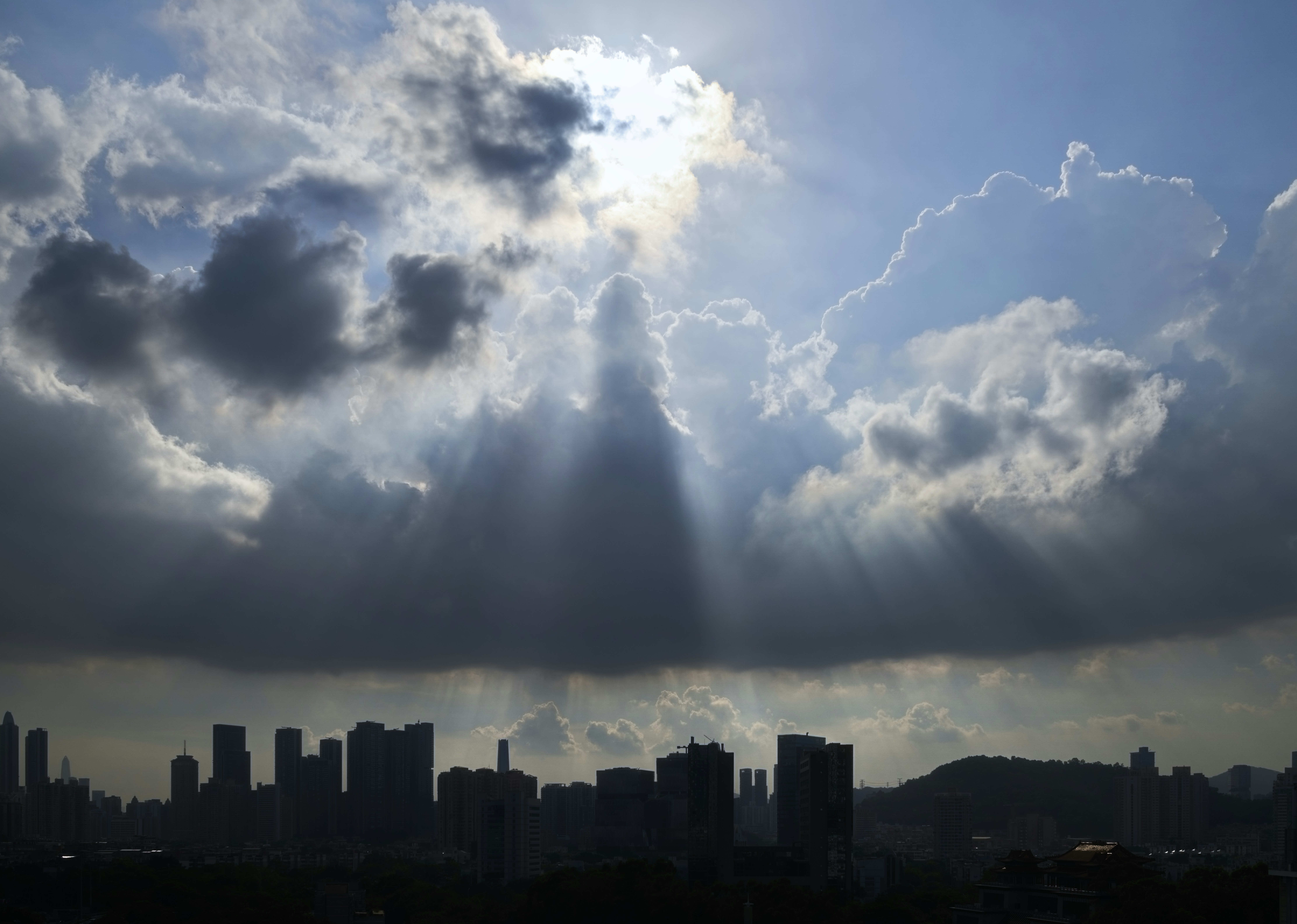 Rays Through a City: Skyline Silhouette Beneath Veiled Sun