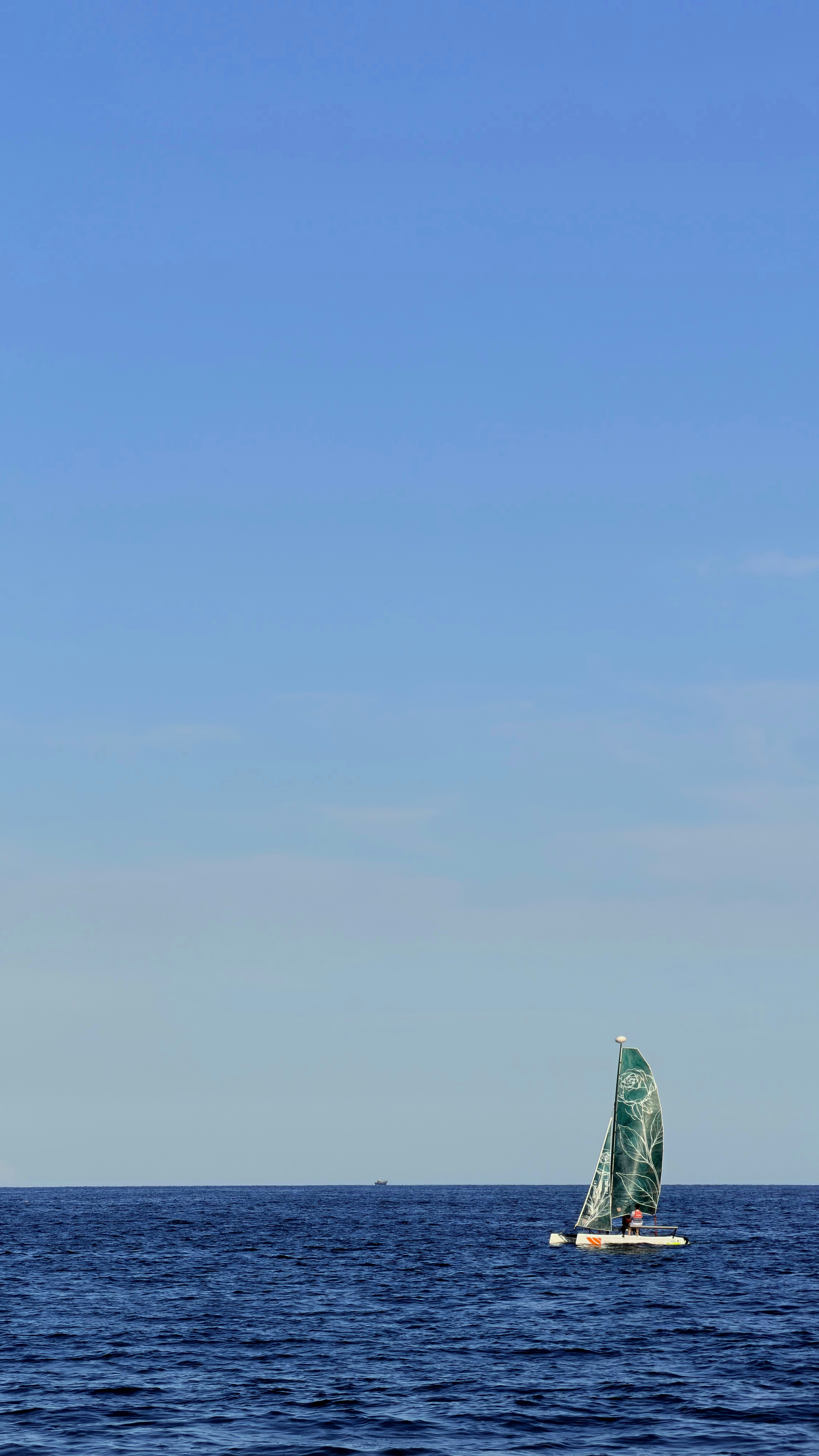 Sail on the Horizon: A Lone Sailboat Beneath a Pacific Sky