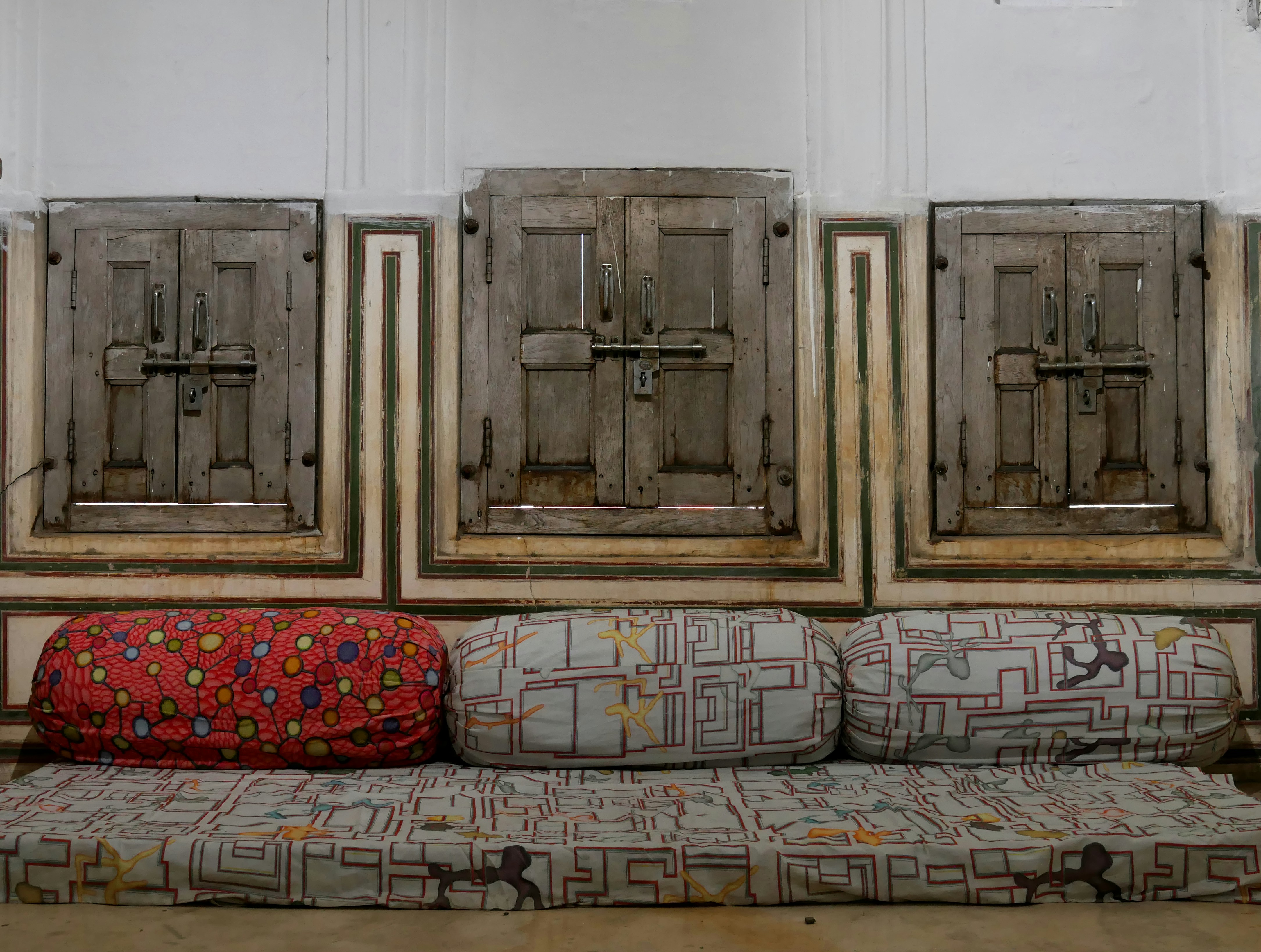 Three Weathered Cabinets Above a Row of Patterned Cushions