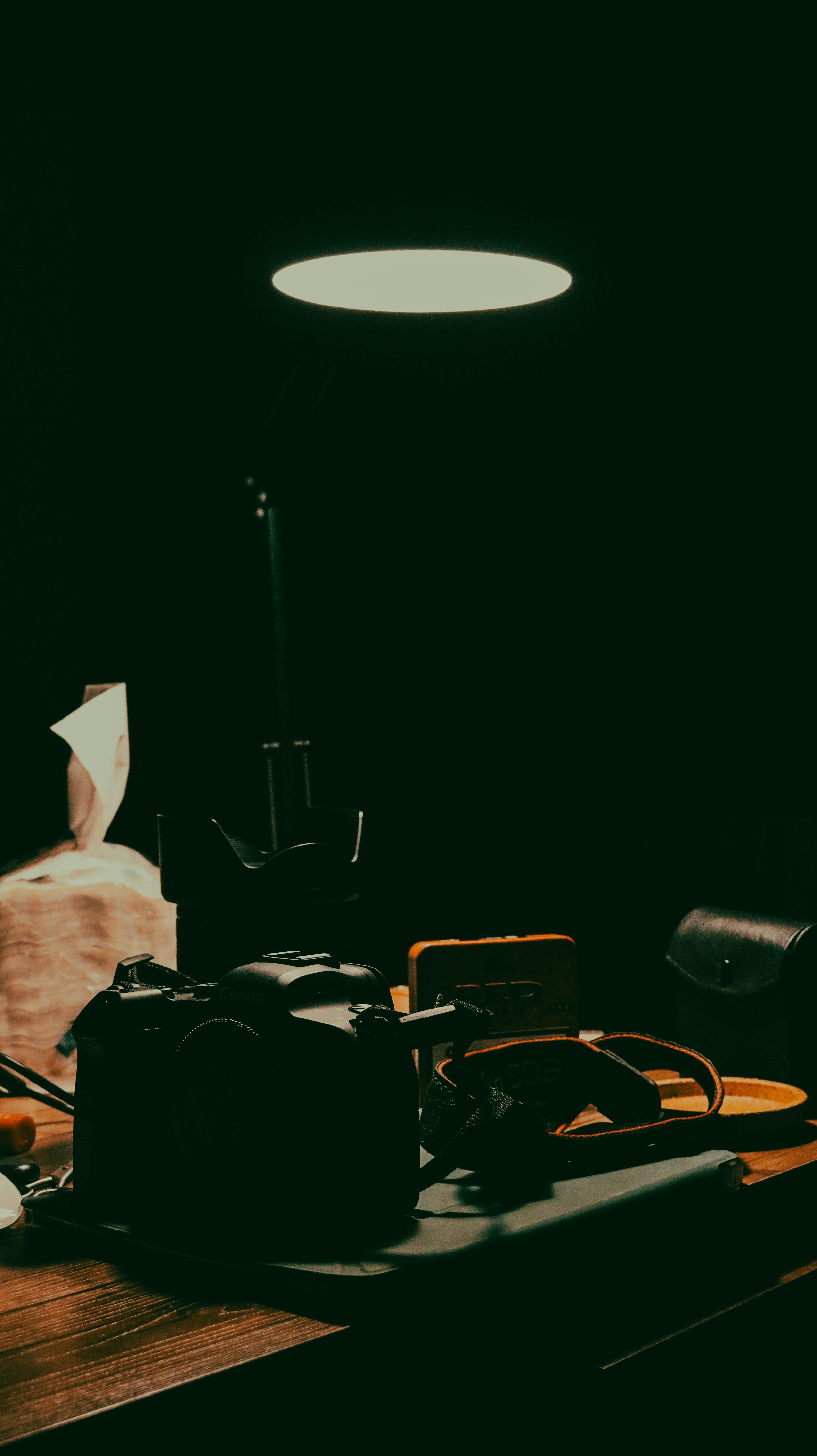 Dim Studio still life: a Canon on the desk under a lone lamp