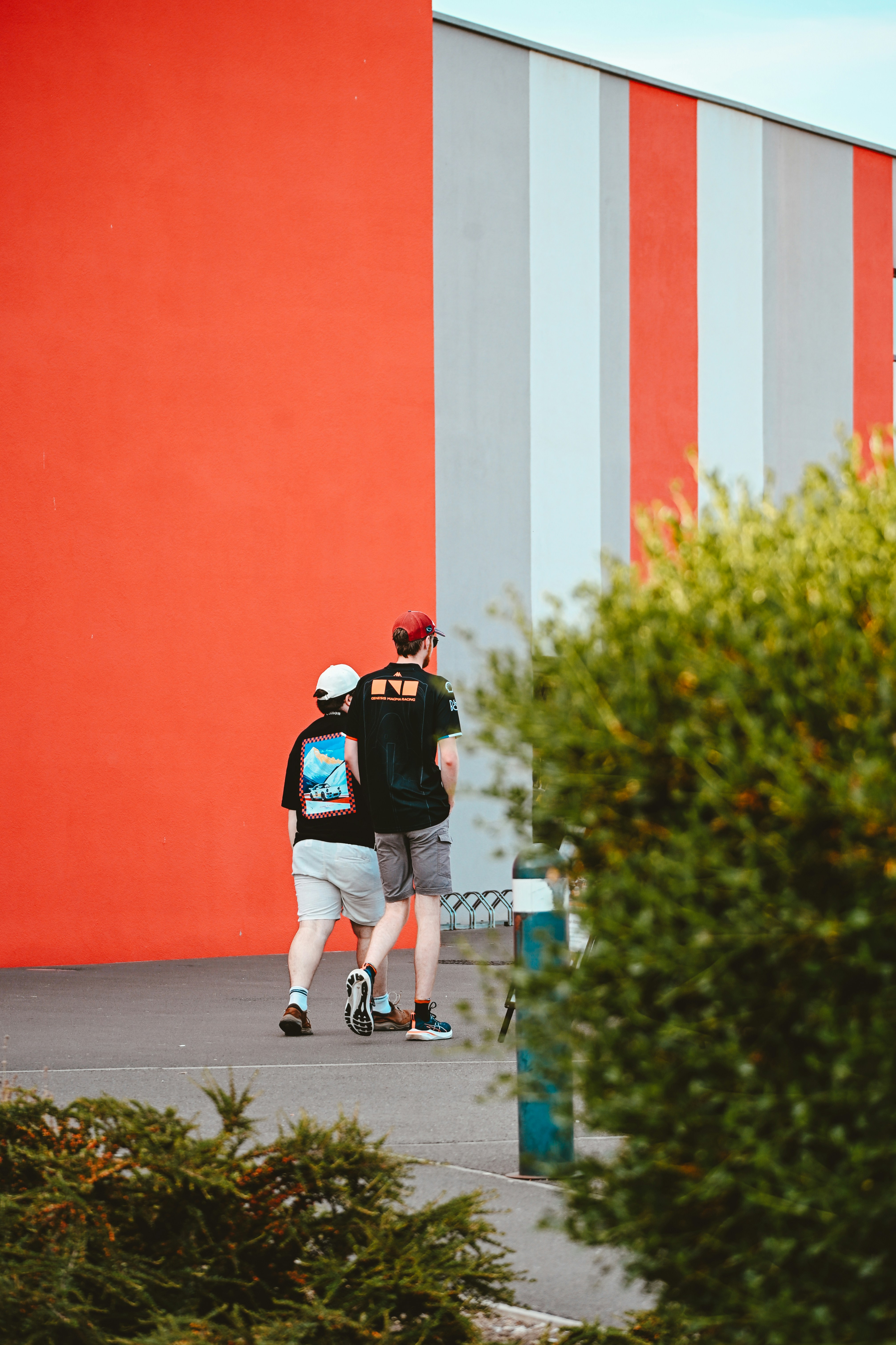 Two Explorers Walk Along a Bold Red Wall