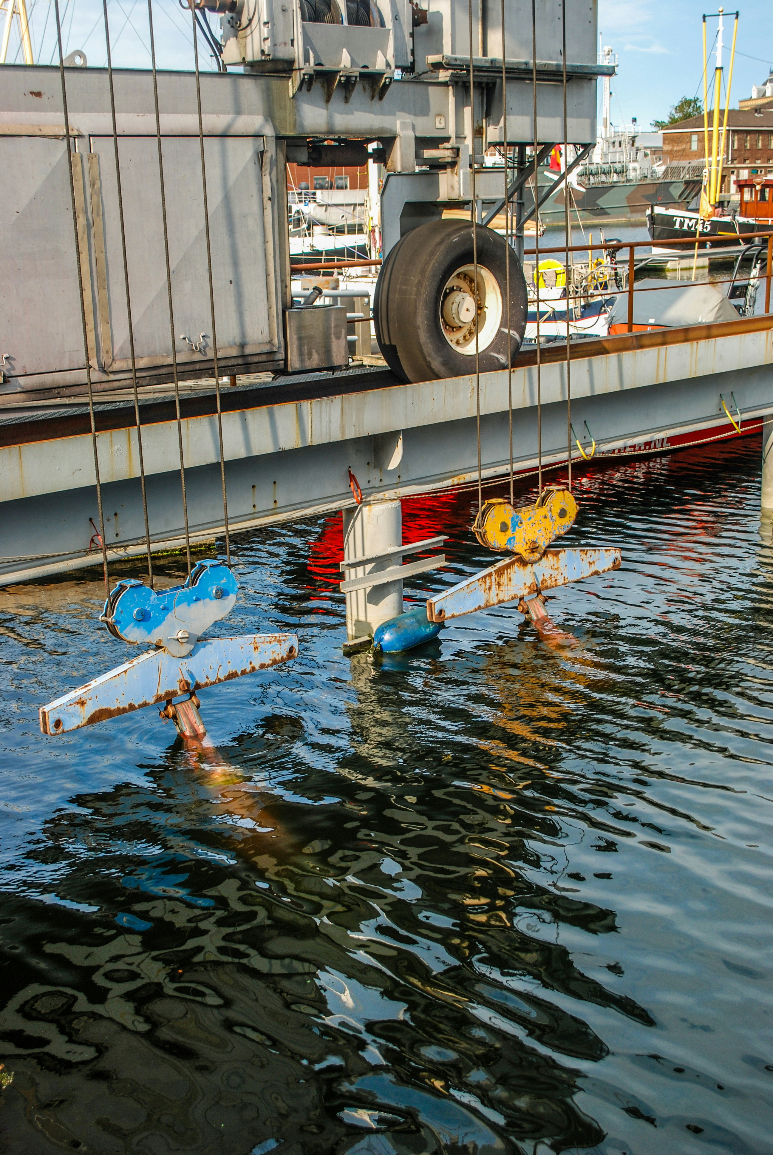 Blue and yellow trolleys suspended above rippling harbor water