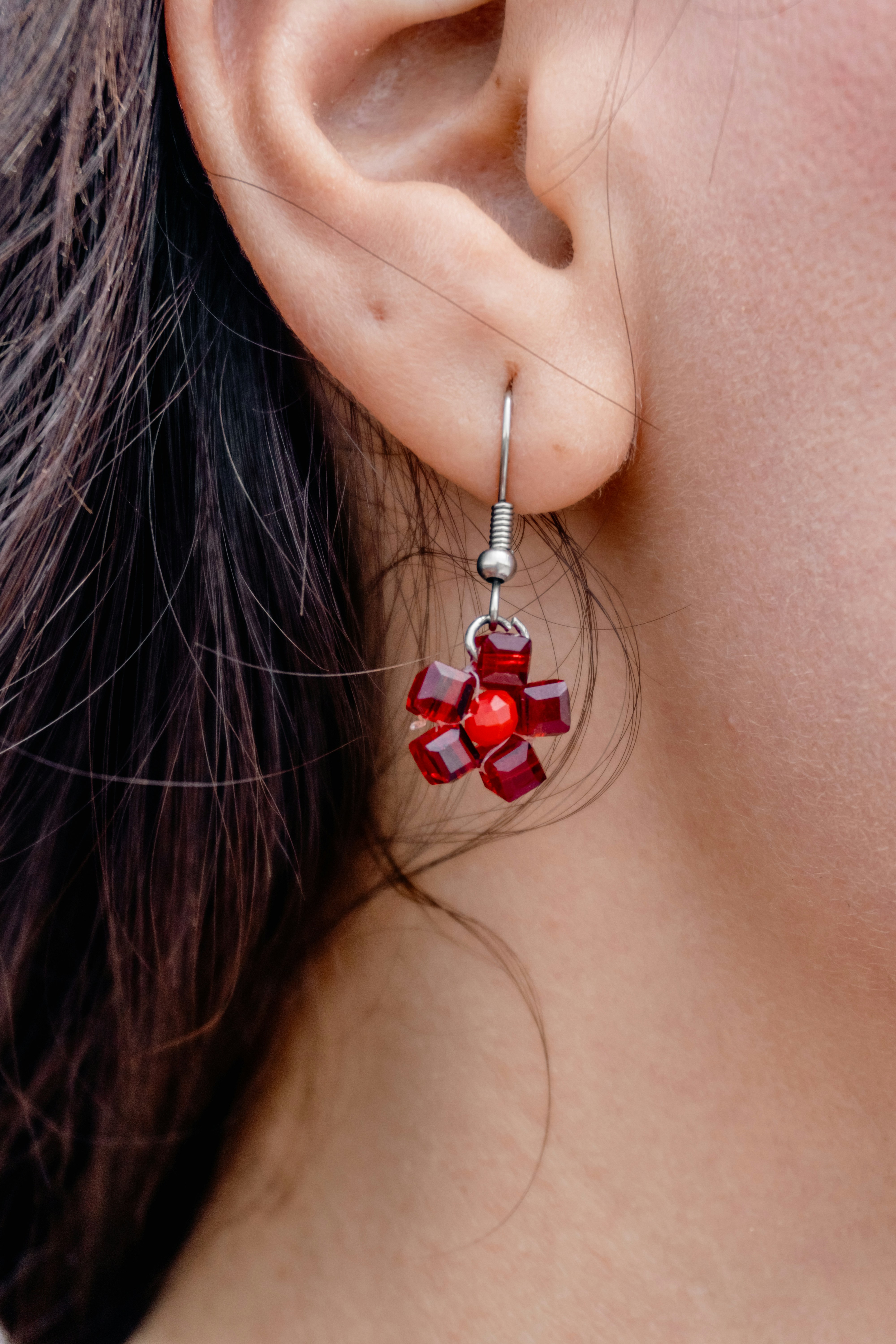 Crimson Bloom: A Glinting Earring Dangles by the Ear