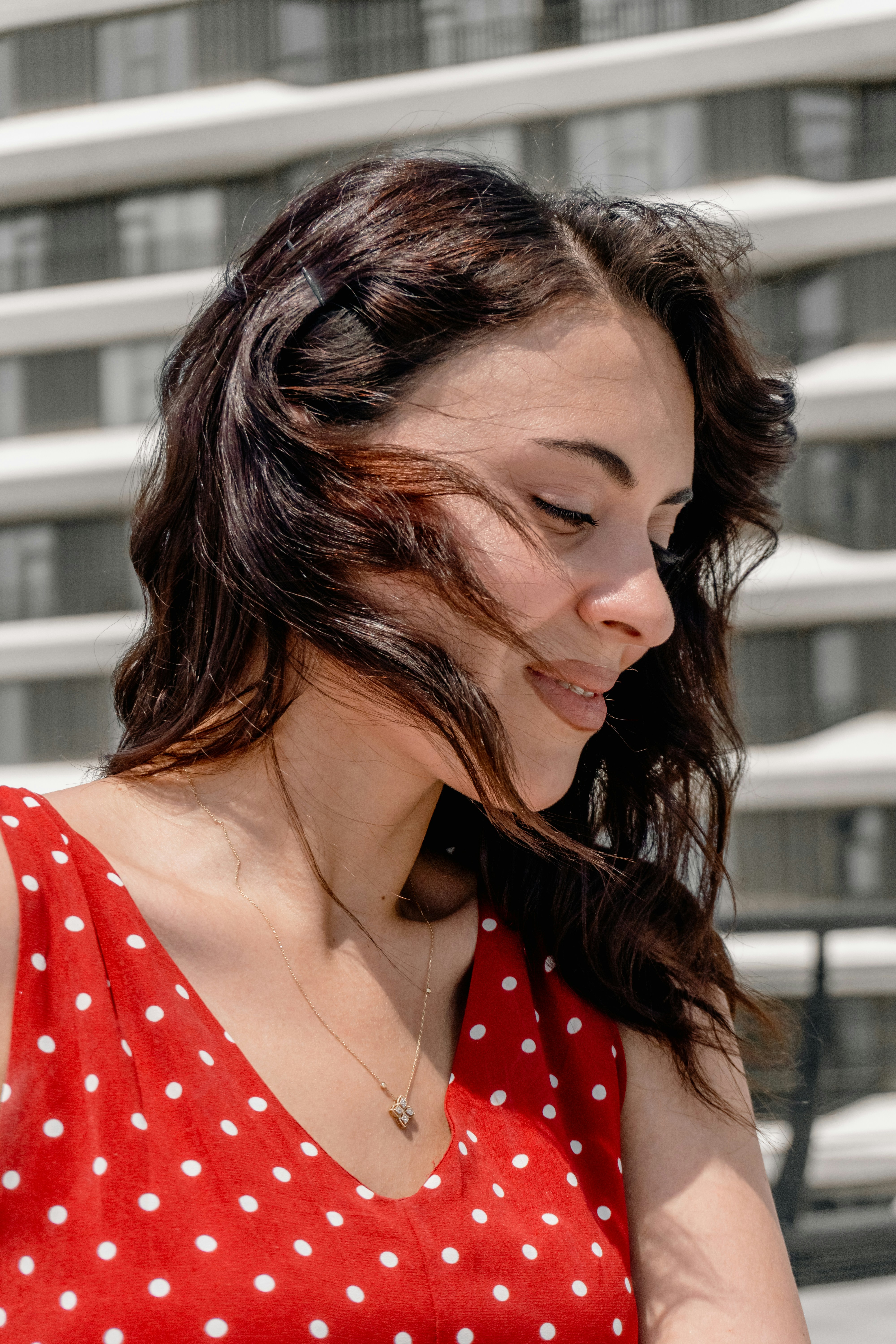Wind in Red: A Portrait of Quiet Joy Against a Modern Facade