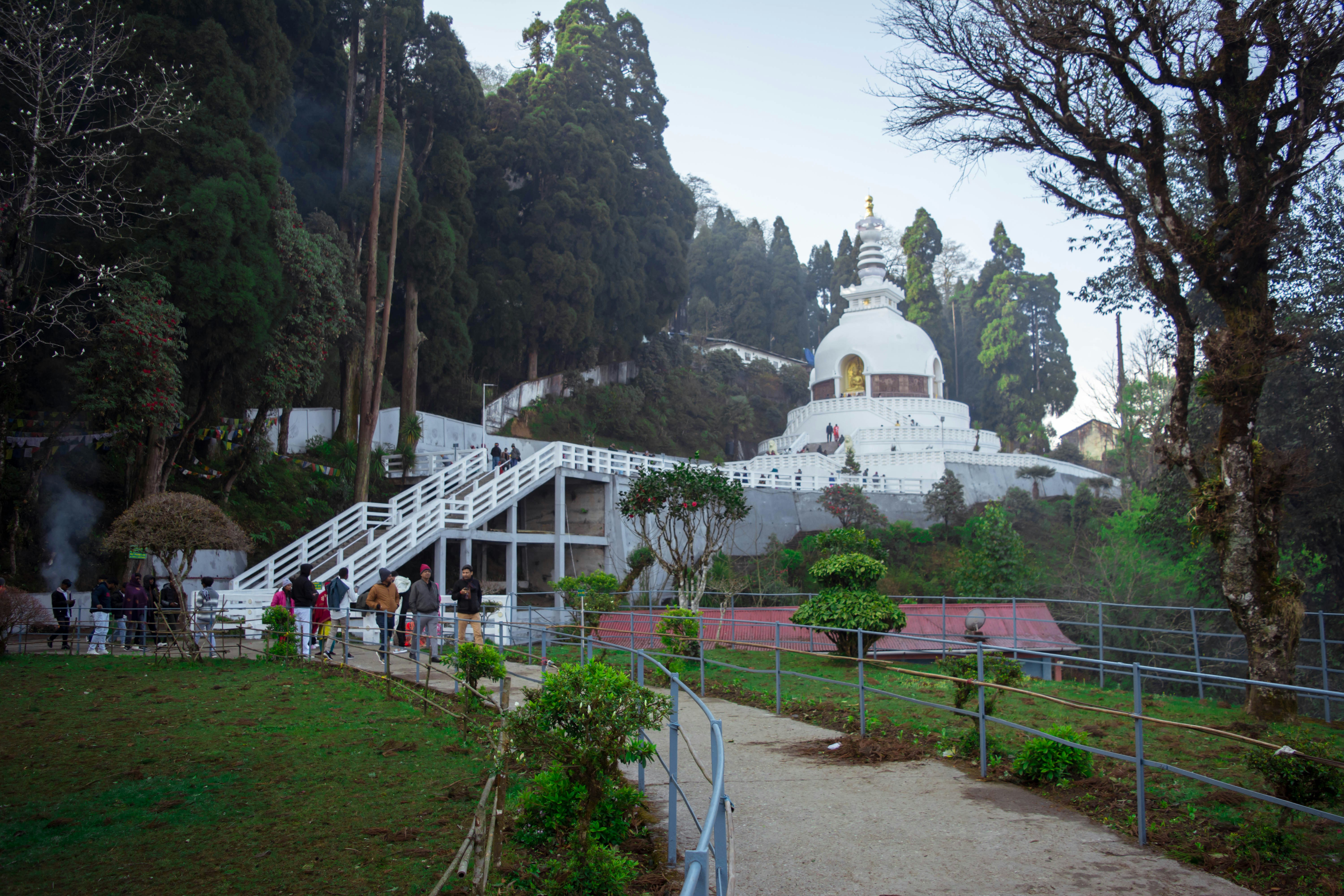 Staircase toward a white temple perched above a tranquil hillside garden
