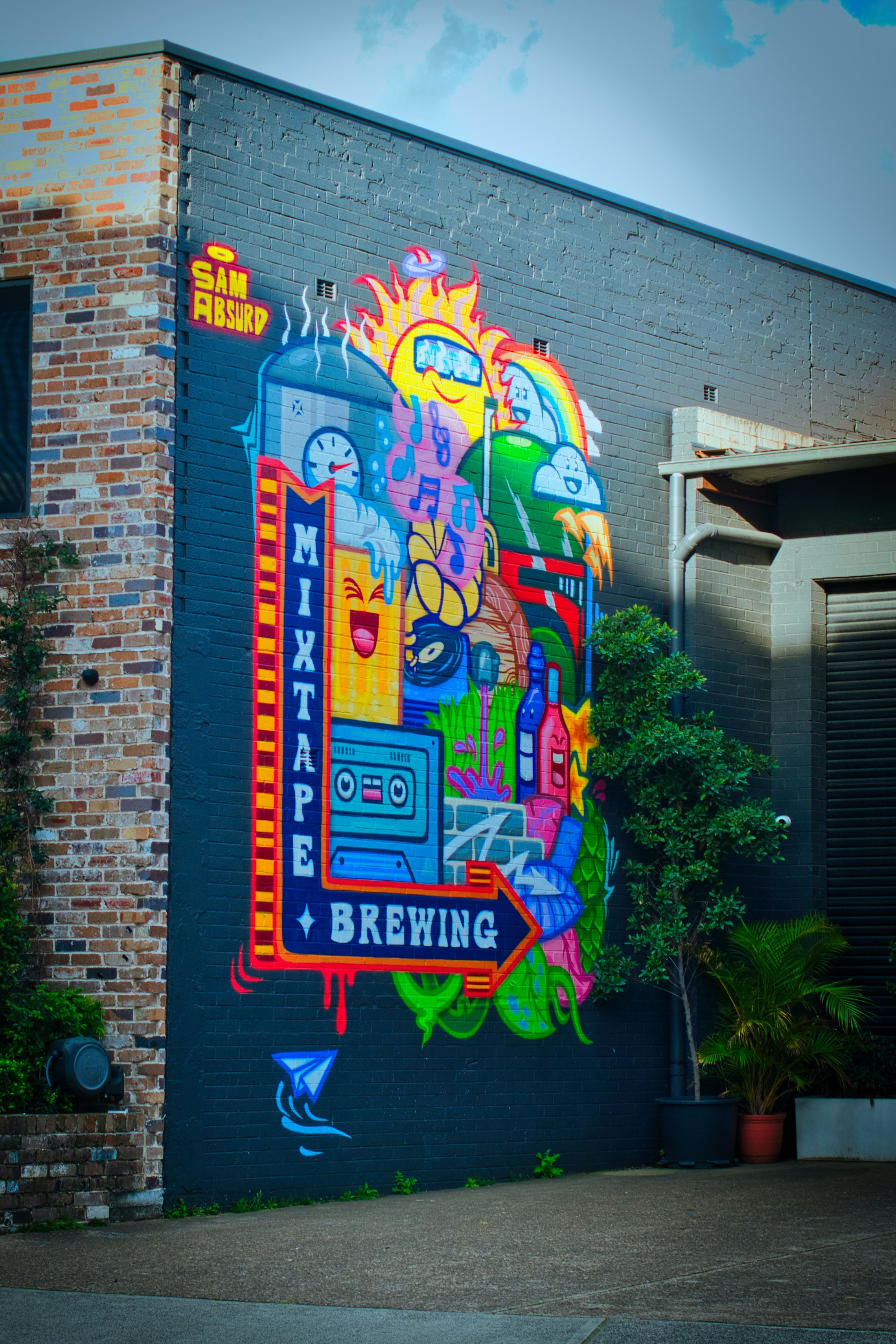 Urban mural of neon-soaked drinks and boomboxes advertising a brewing mixer