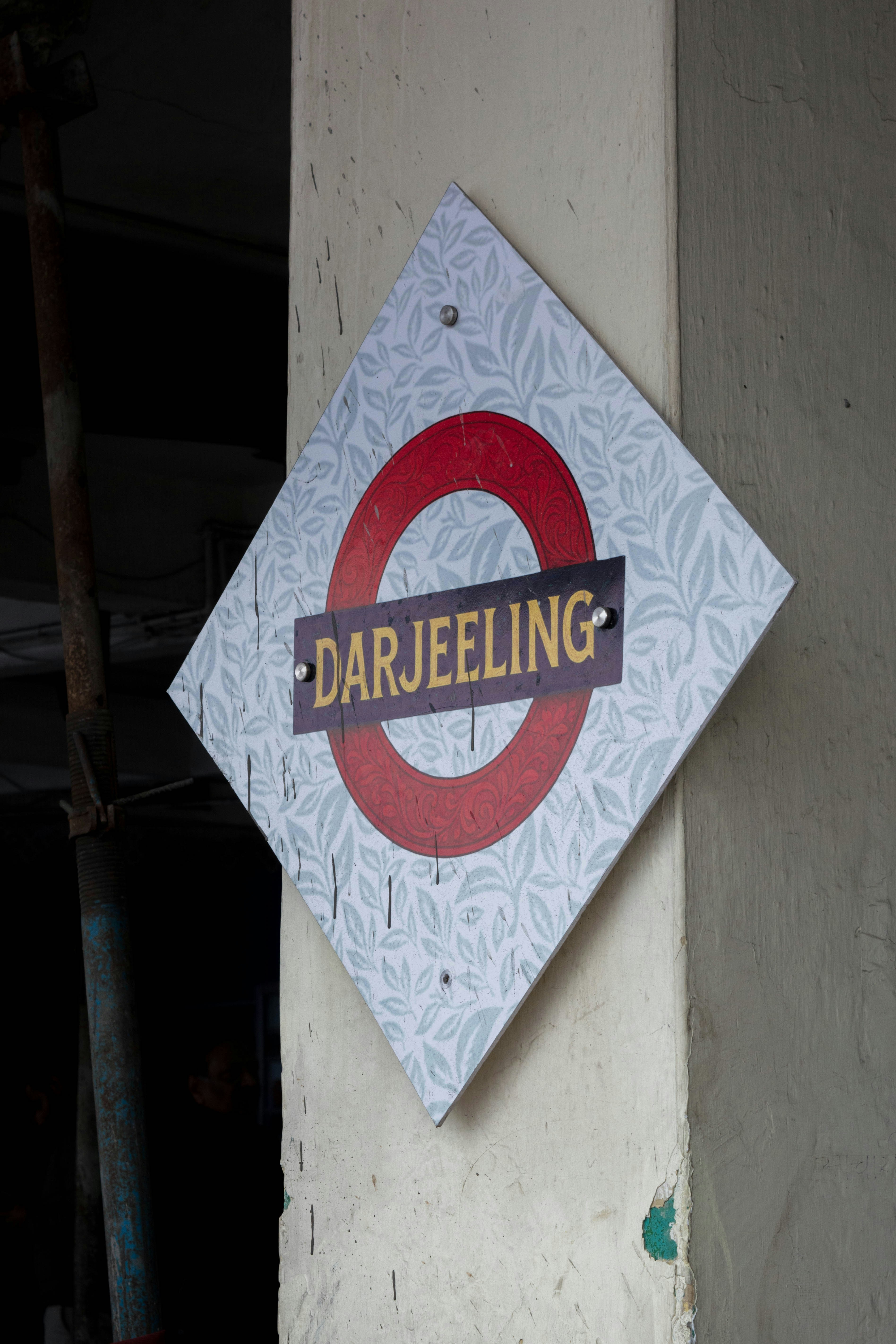 Diamond Sign with Darjeeling Emblem Beside a Shadowed Entrance