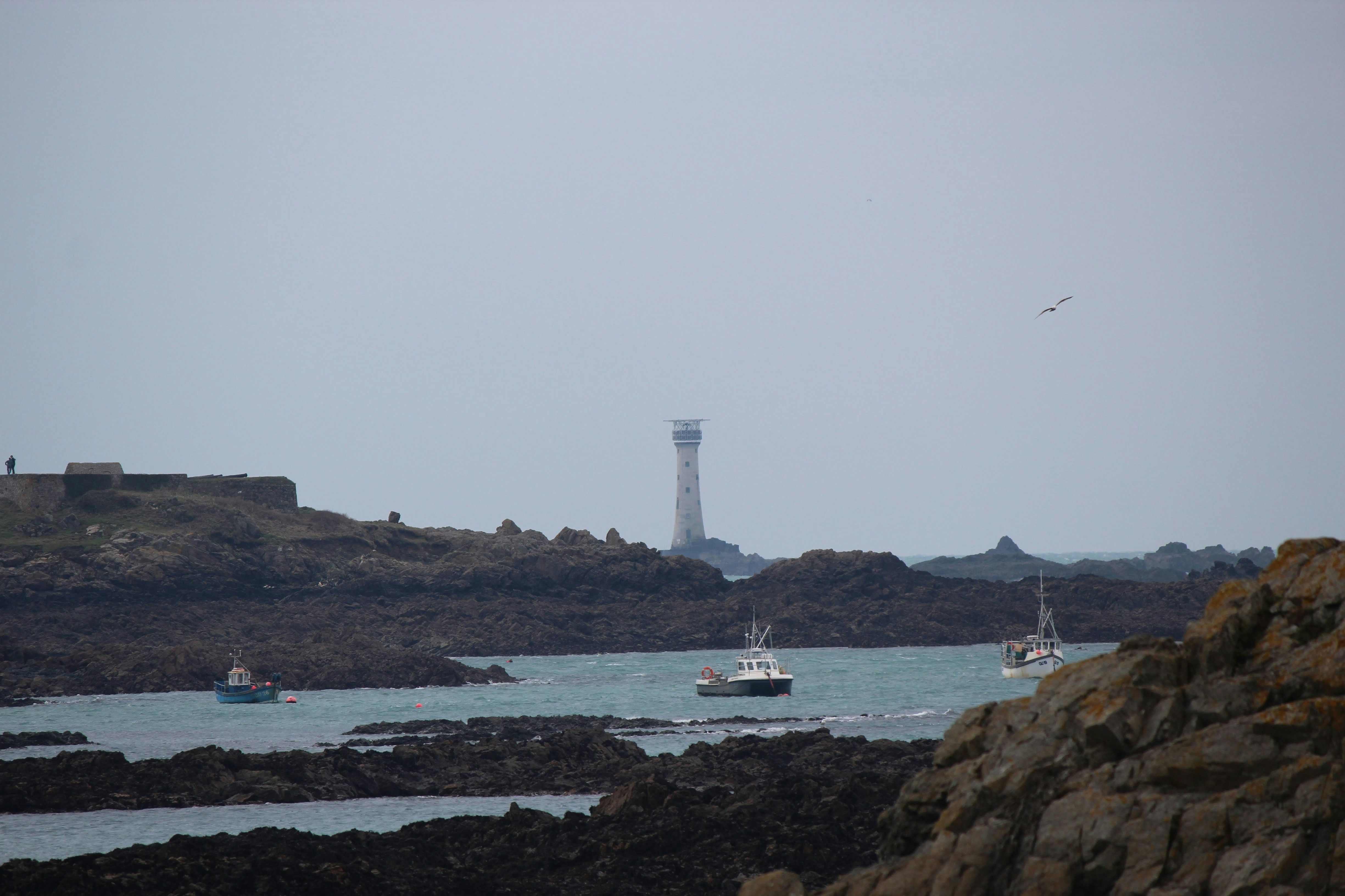 Coastal Watch: Boats and Lighthouse on a Quiet Horizon