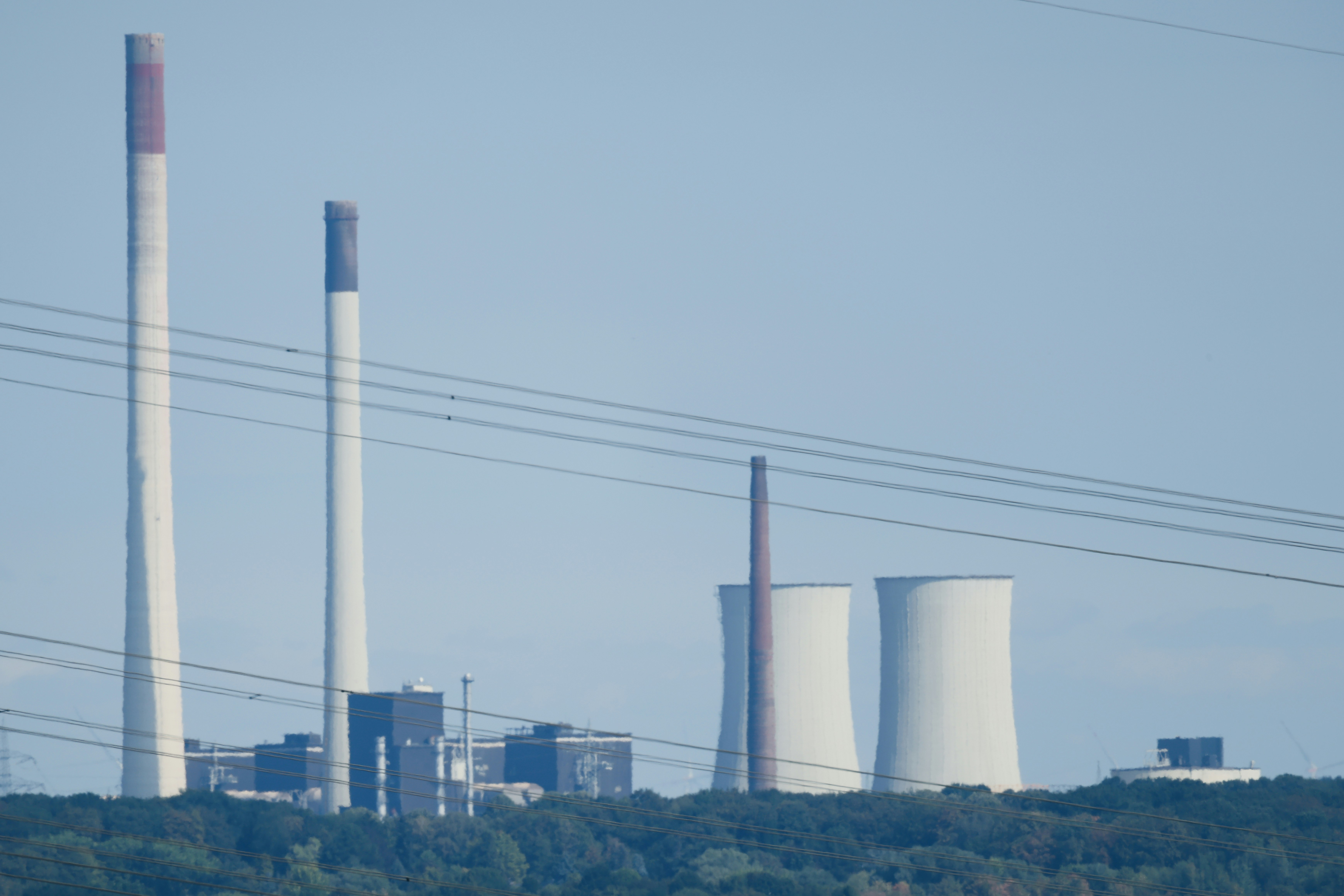 Industrial silhouettes: cooling towers and smokestacks over a forested horizon