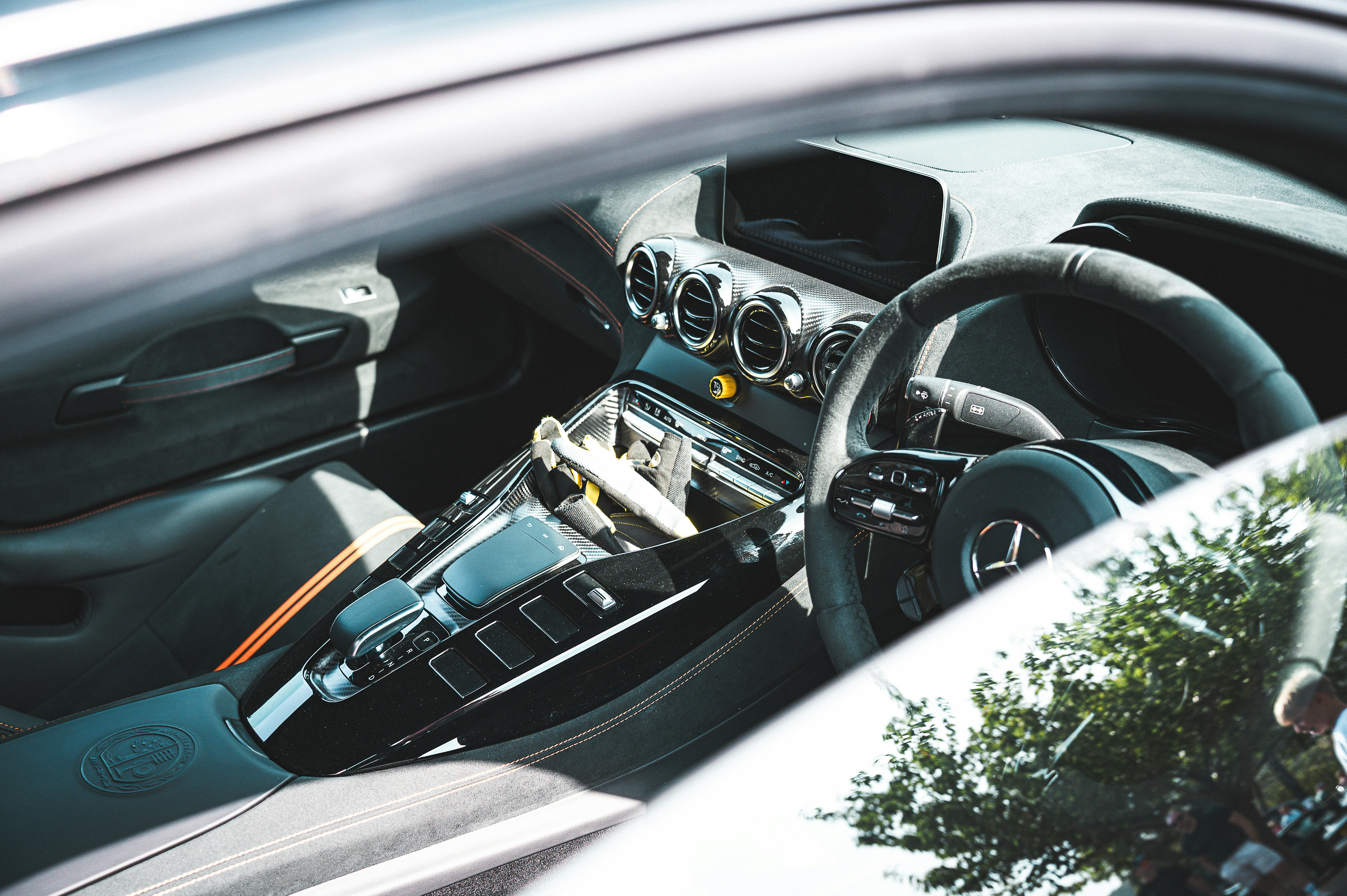 Close-up view of a premium car cabin showcasing the center console, climate vents, and steering wheel with metallic accents and leather trim.
