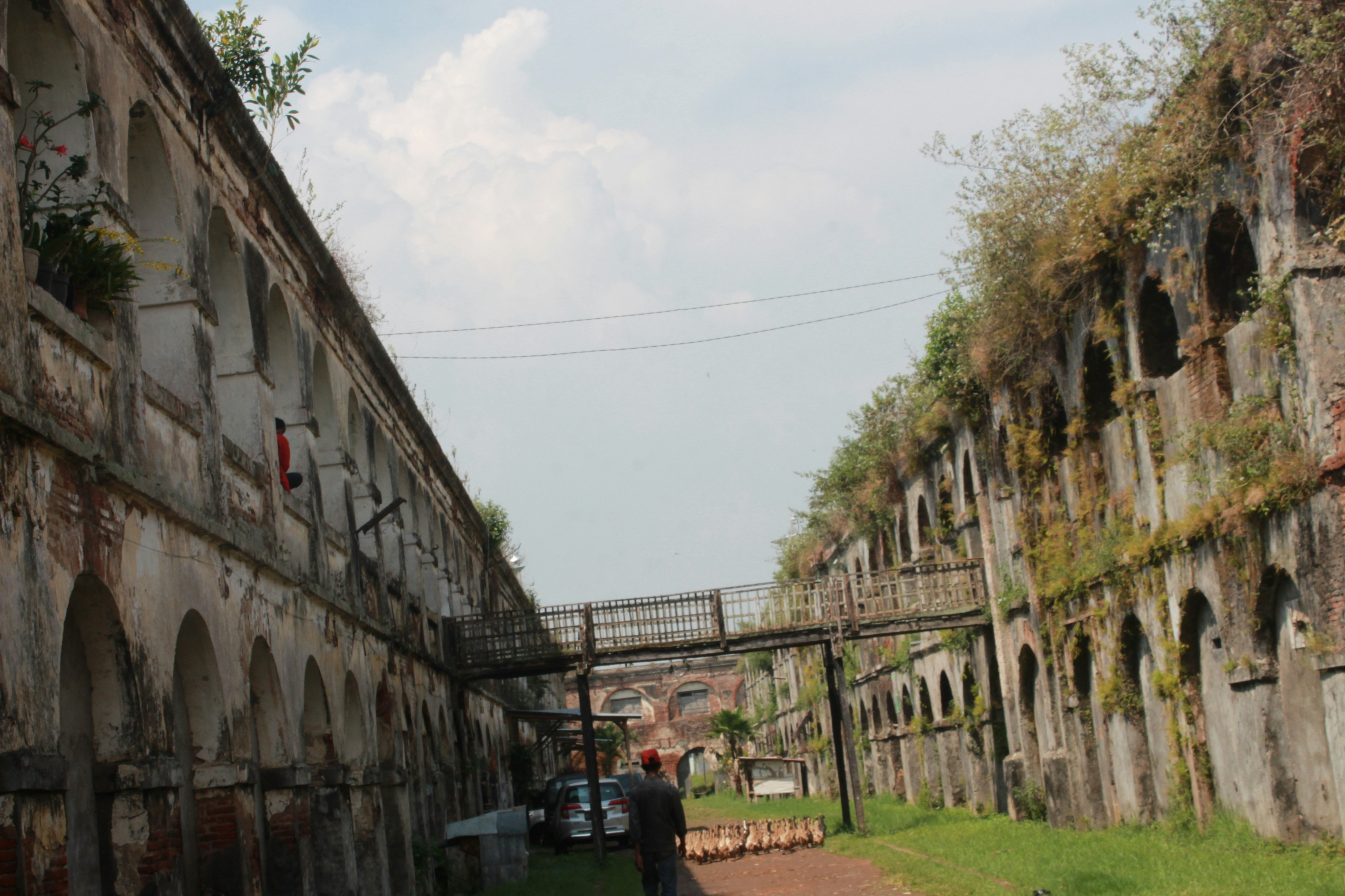 Aged arches and a quiet courtyard: bricks, vines, and distant figures