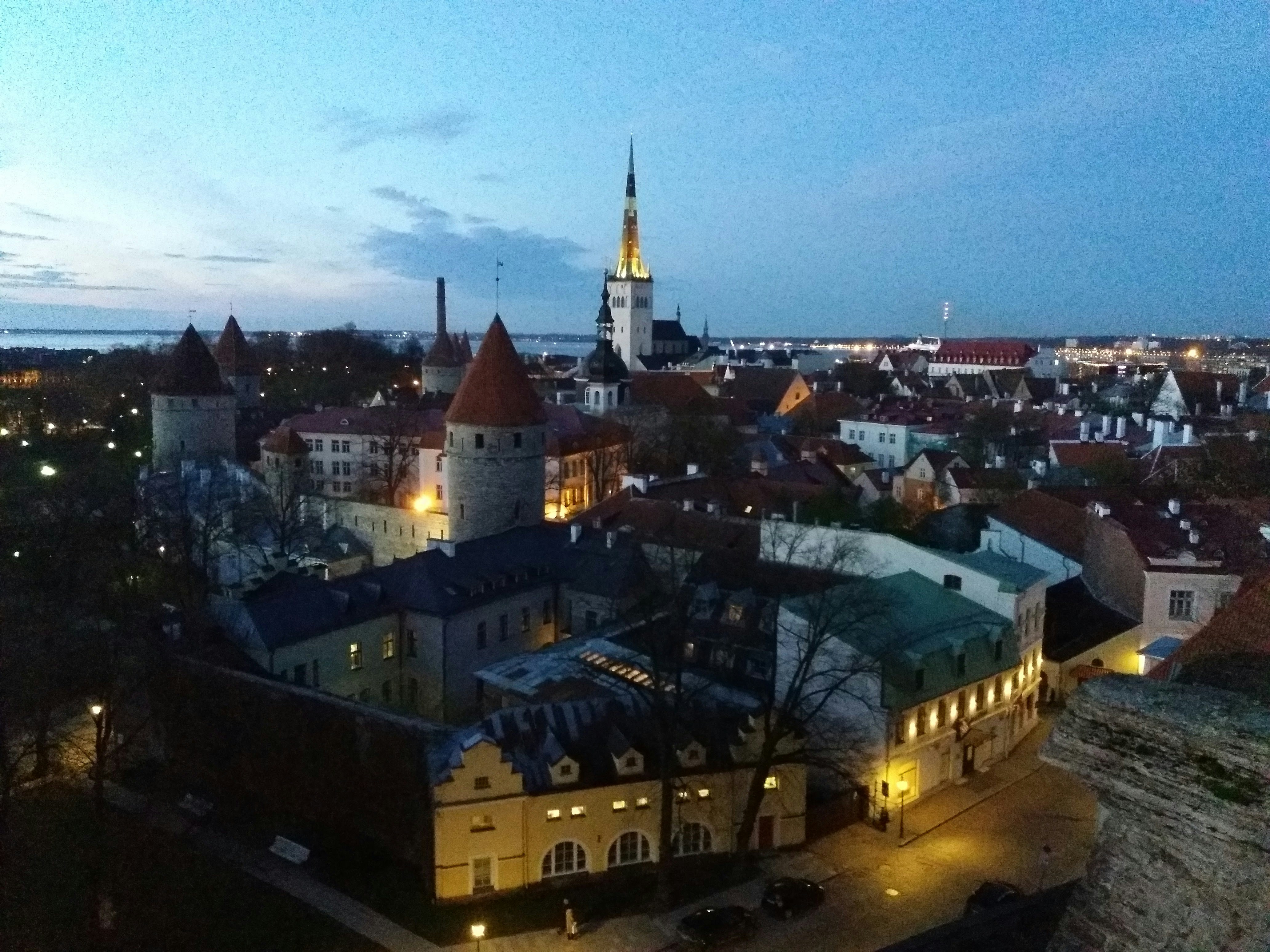 Nightfall over a turreted town: warm streetlights cradle a medieval skyline