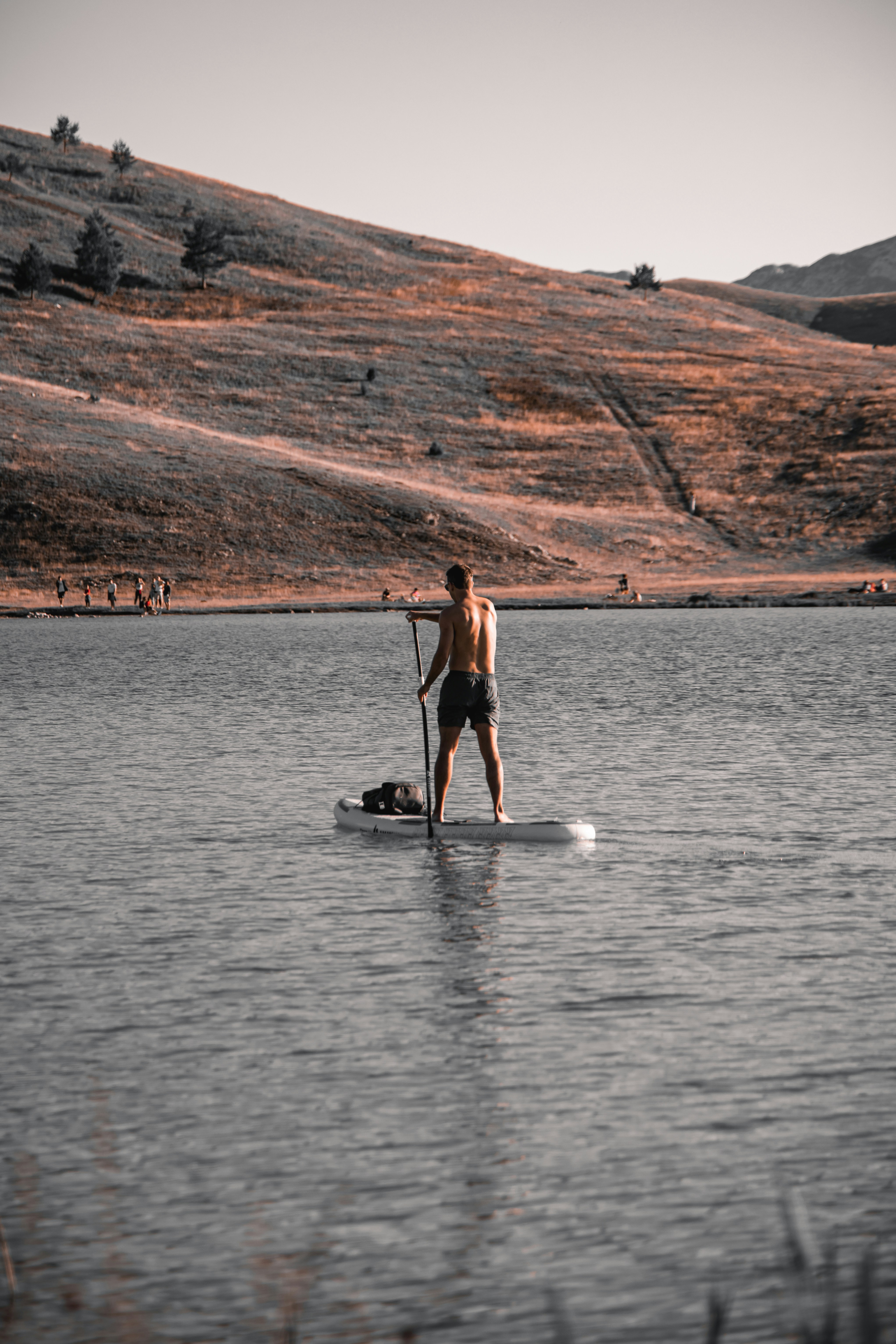 Stand-Up Paddle at Dusk: Lone Rider on Quiet Waters