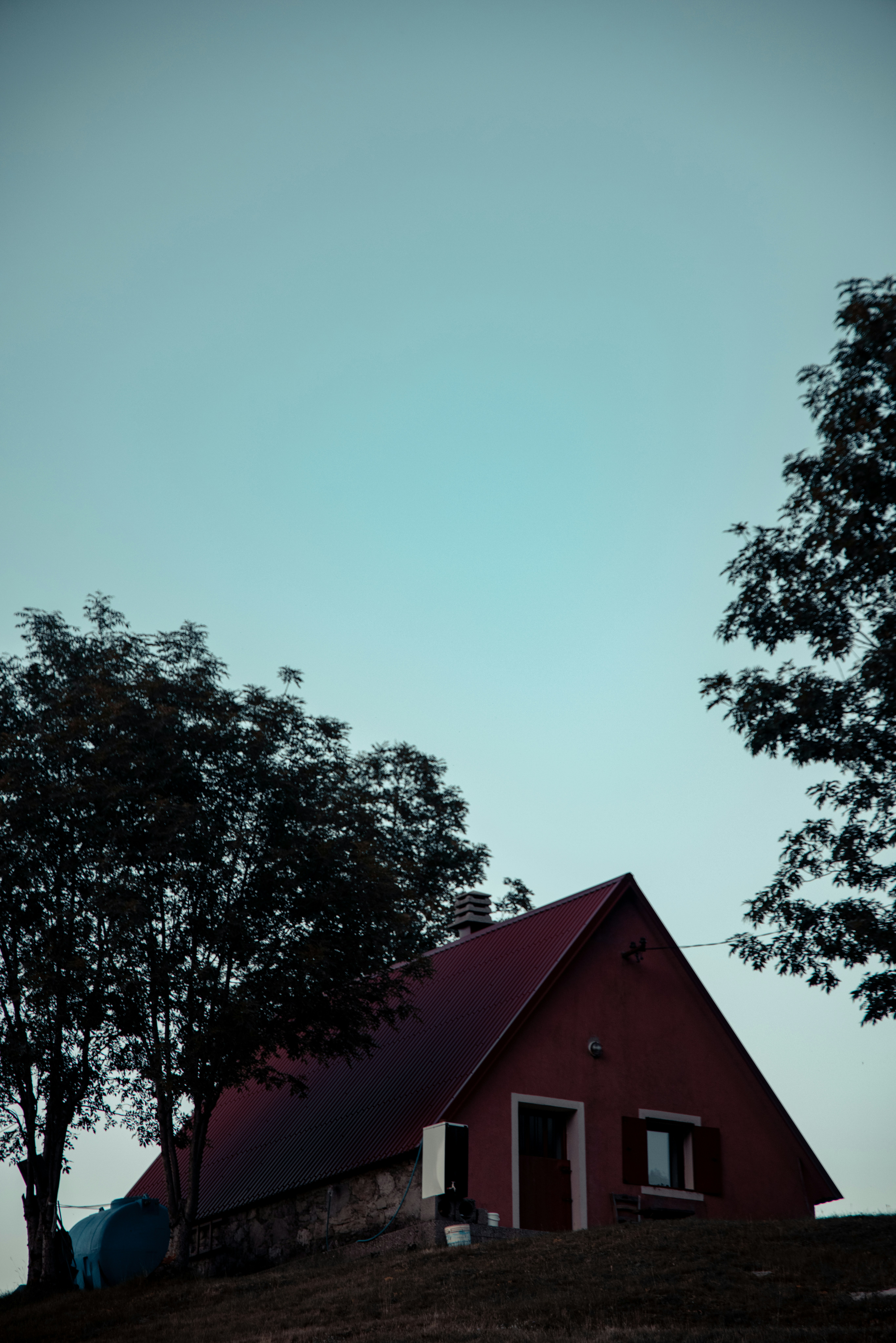 Red-roofed cottage on a gentle hill beneath a calm sky