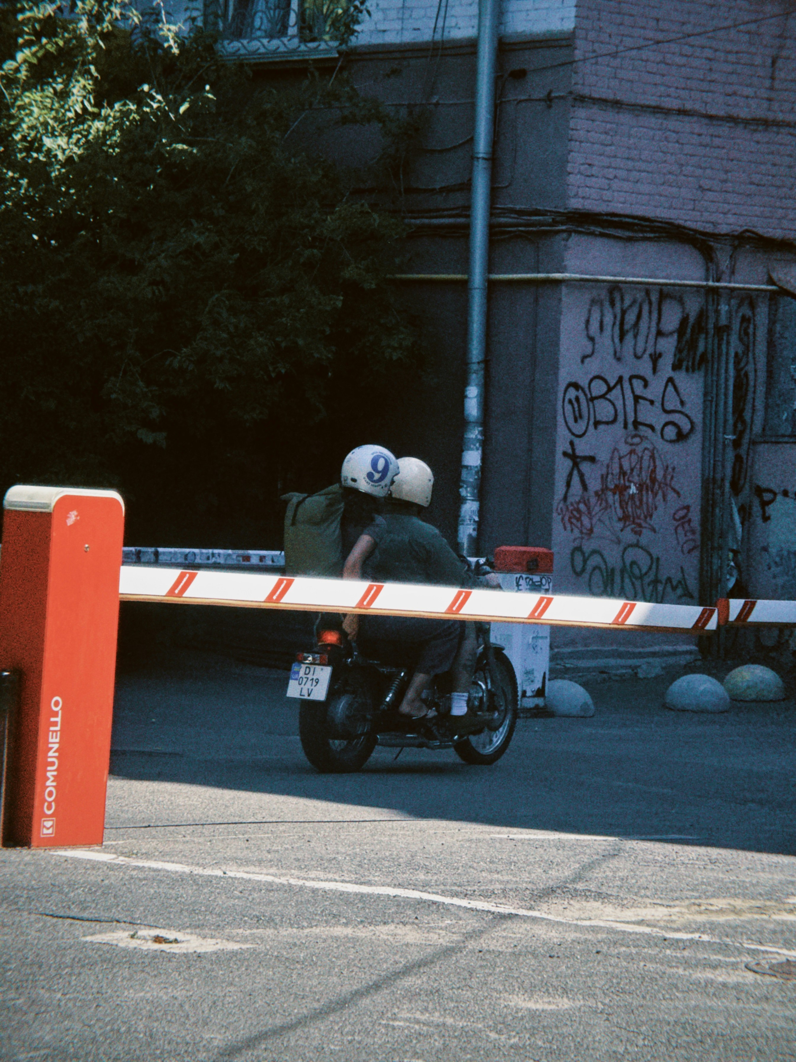 Motorcycle Barrier: Two Helmets under a Graffitied Wall
