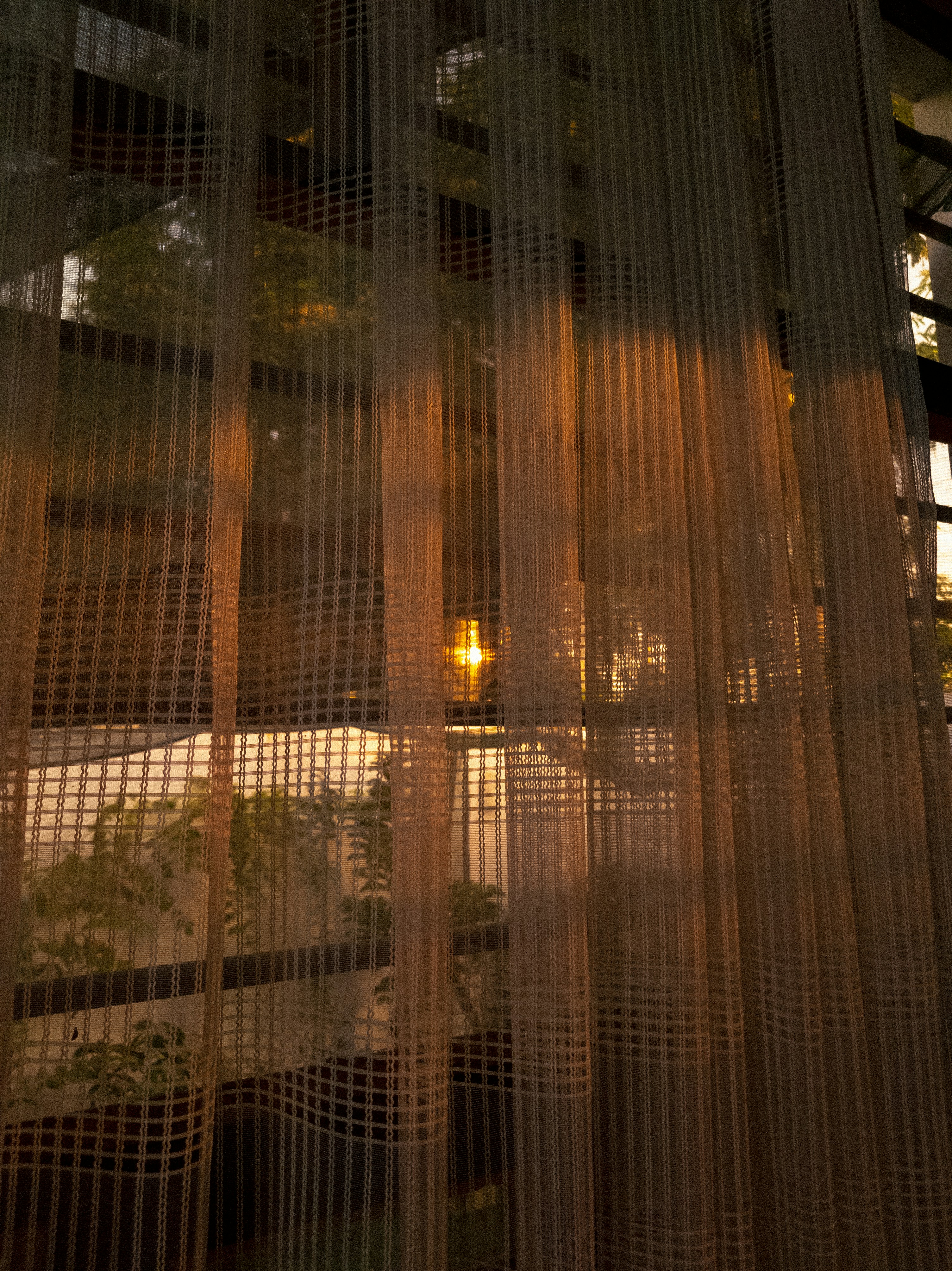 Warm backlit curtain veils a quiet balcony scene
