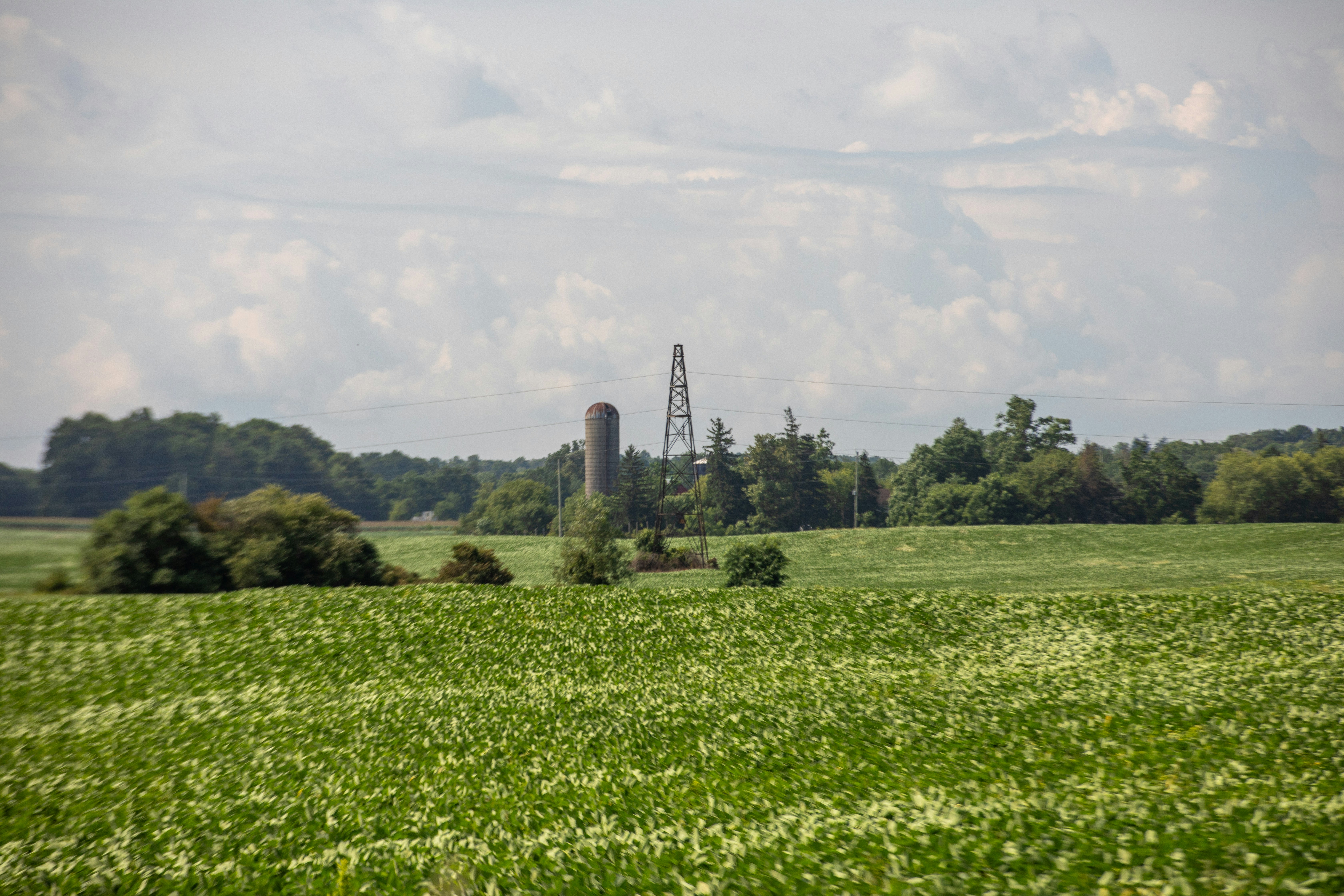 Rural Horizon: Field, Silo, and Transmission Tower Under Expansive Sky